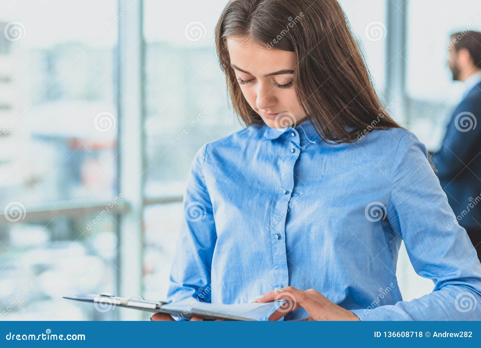 The Secretary with a Folder and Documents is in the Office. during this ...