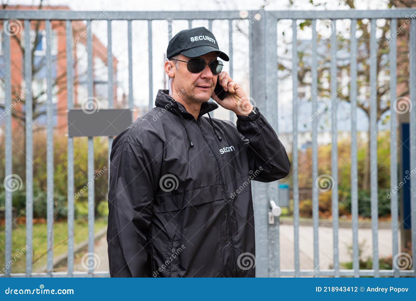 Security Guard Talking on Mobile Phone in Front of Gate Stock Photo ...