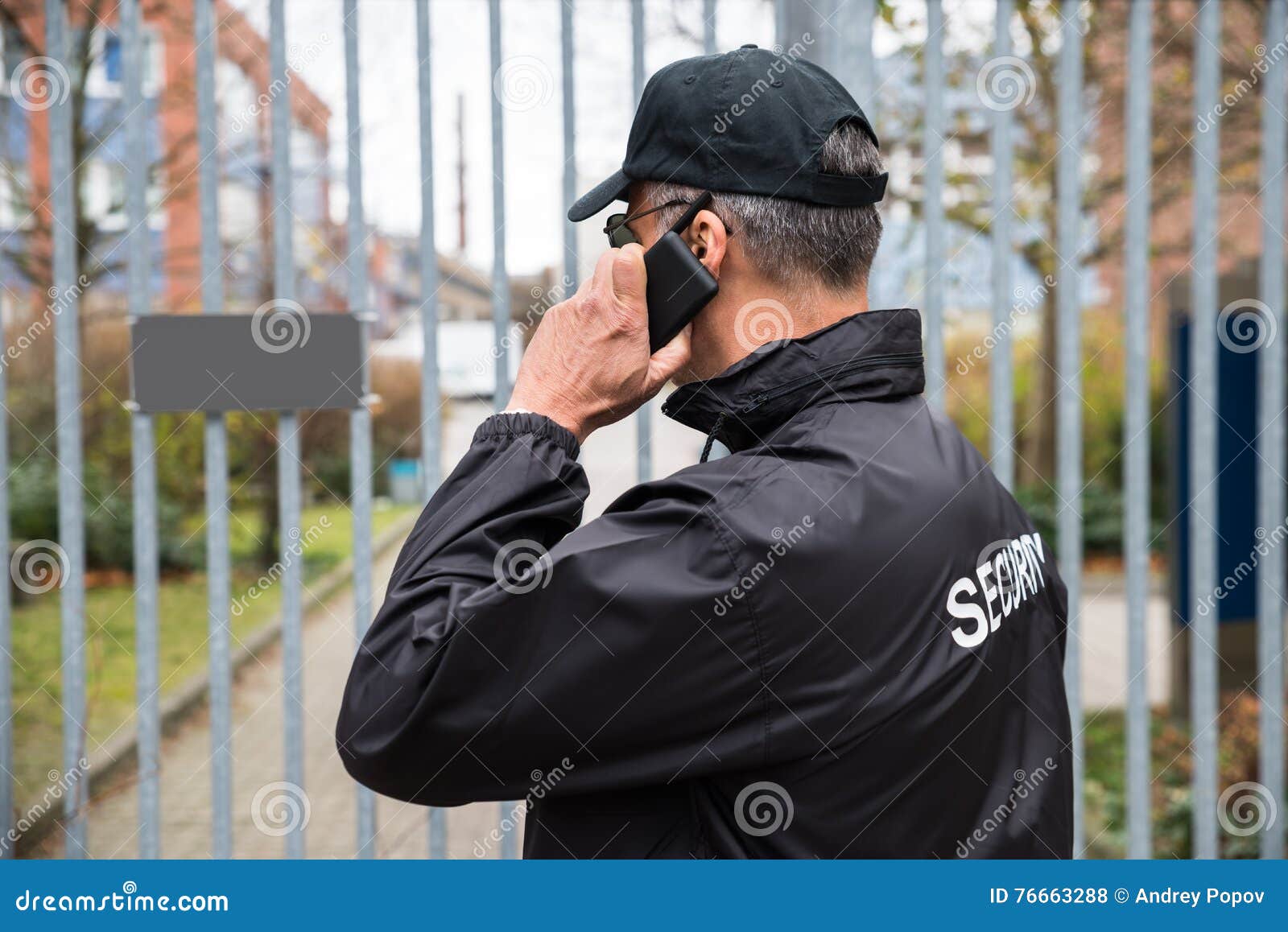 Security Guard Talking on Mobile Phone in Front of Gate Stock Photo ...