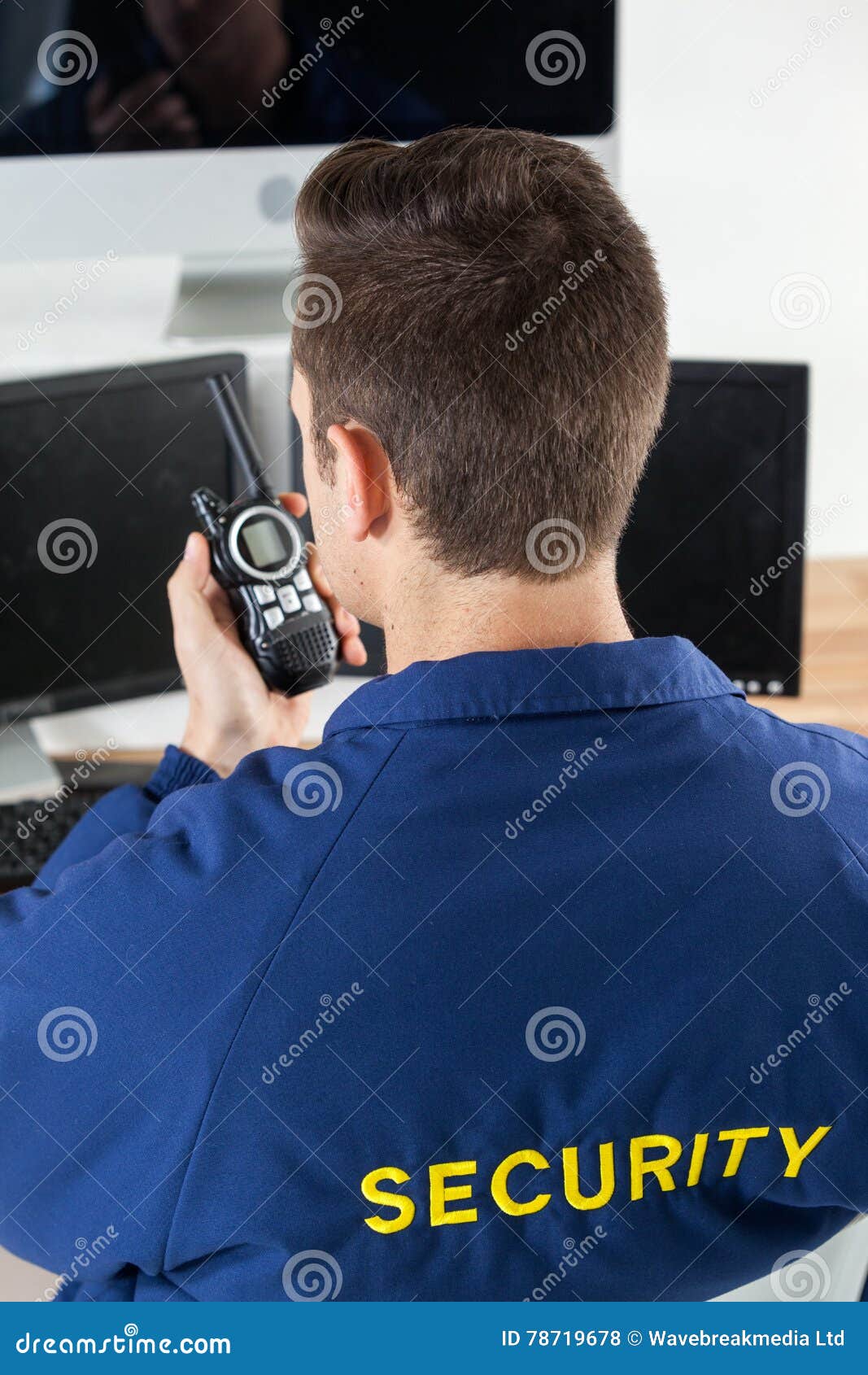Security Officer Talking on Walkie-talkie while Looking at Computer ...