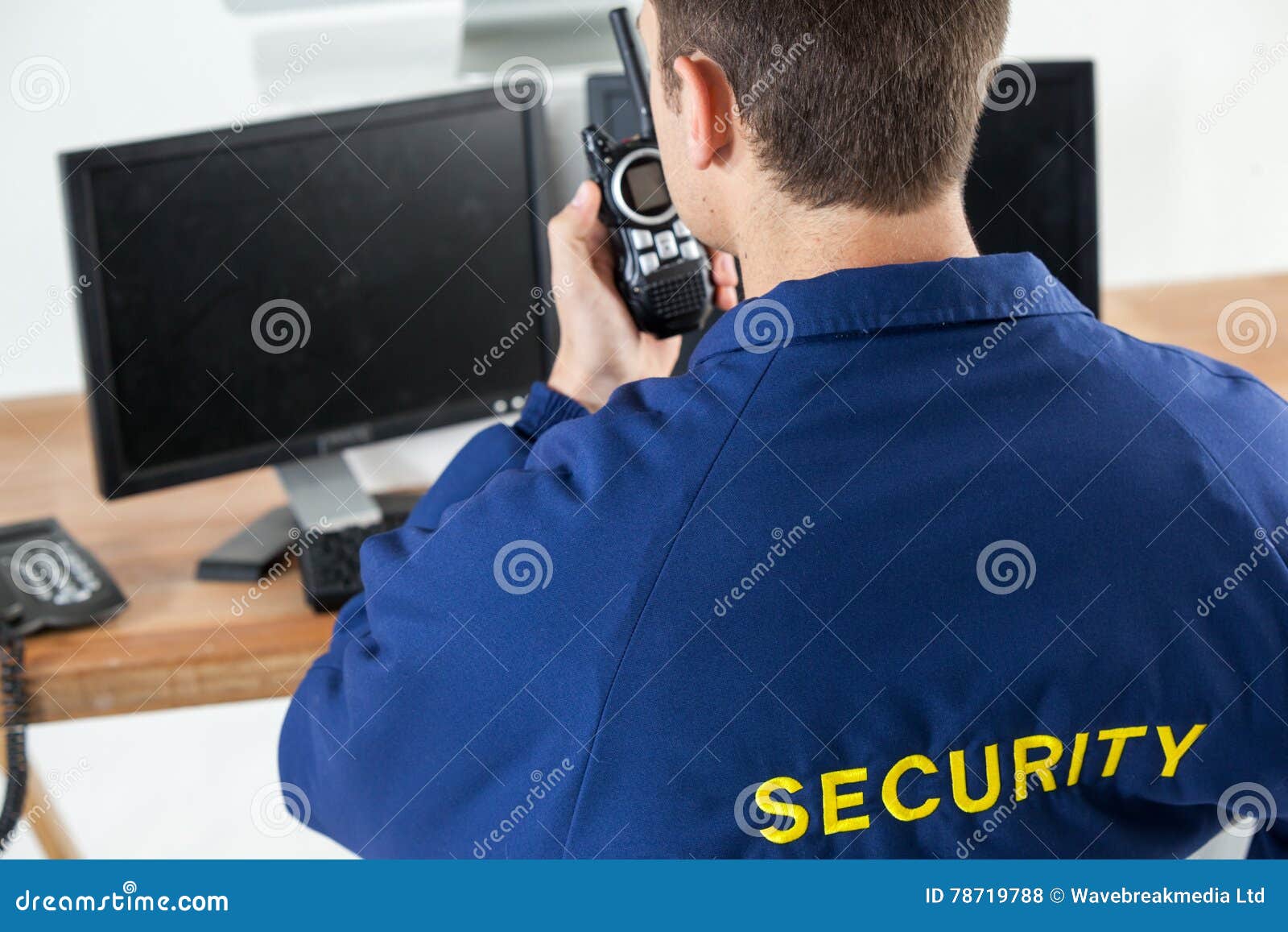 Security Officer Talking on Walkie-talkie while Looking at Computer ...
