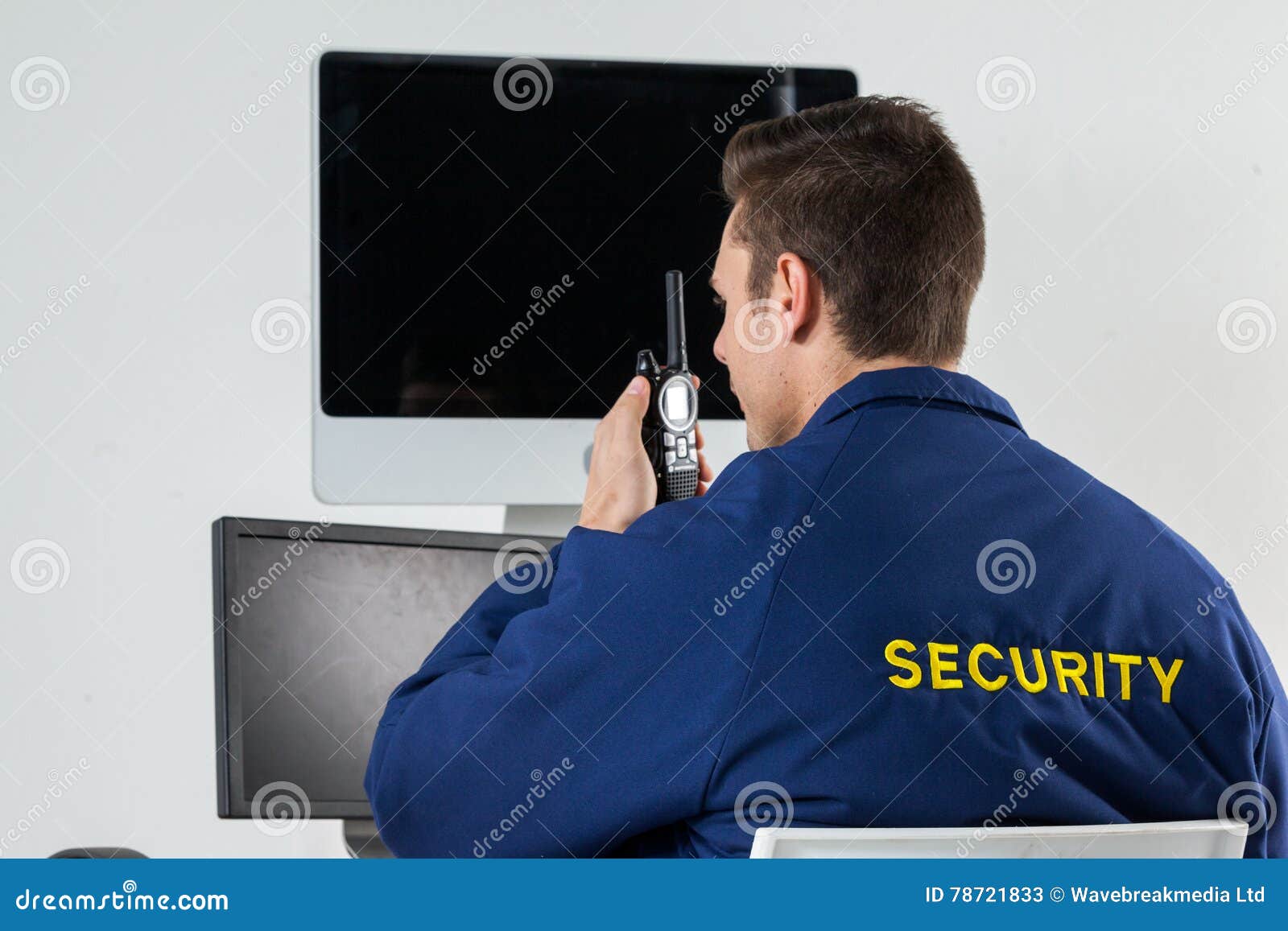 Security Officer Talking on Walkie-talkie while Looking at Computer ...