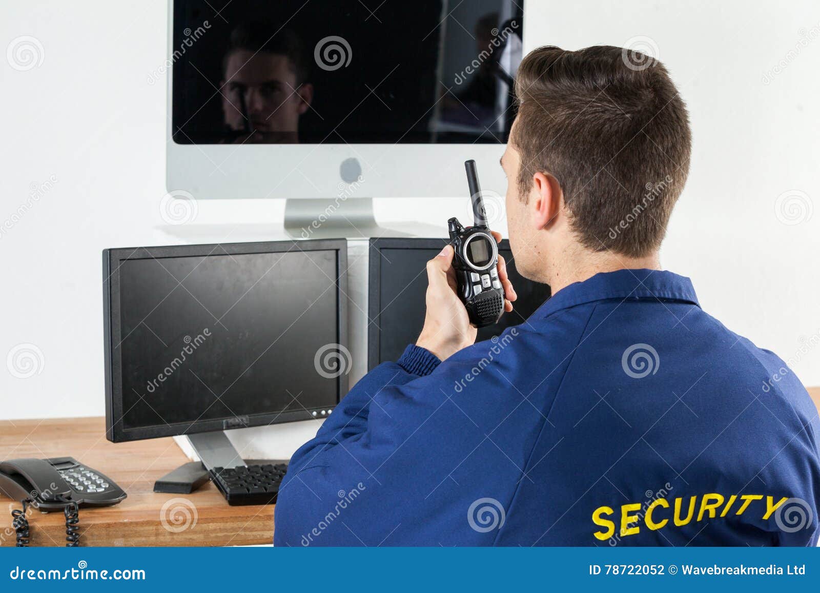 Security Officer Talking on Walkie-talkie while Looking at Computer ...