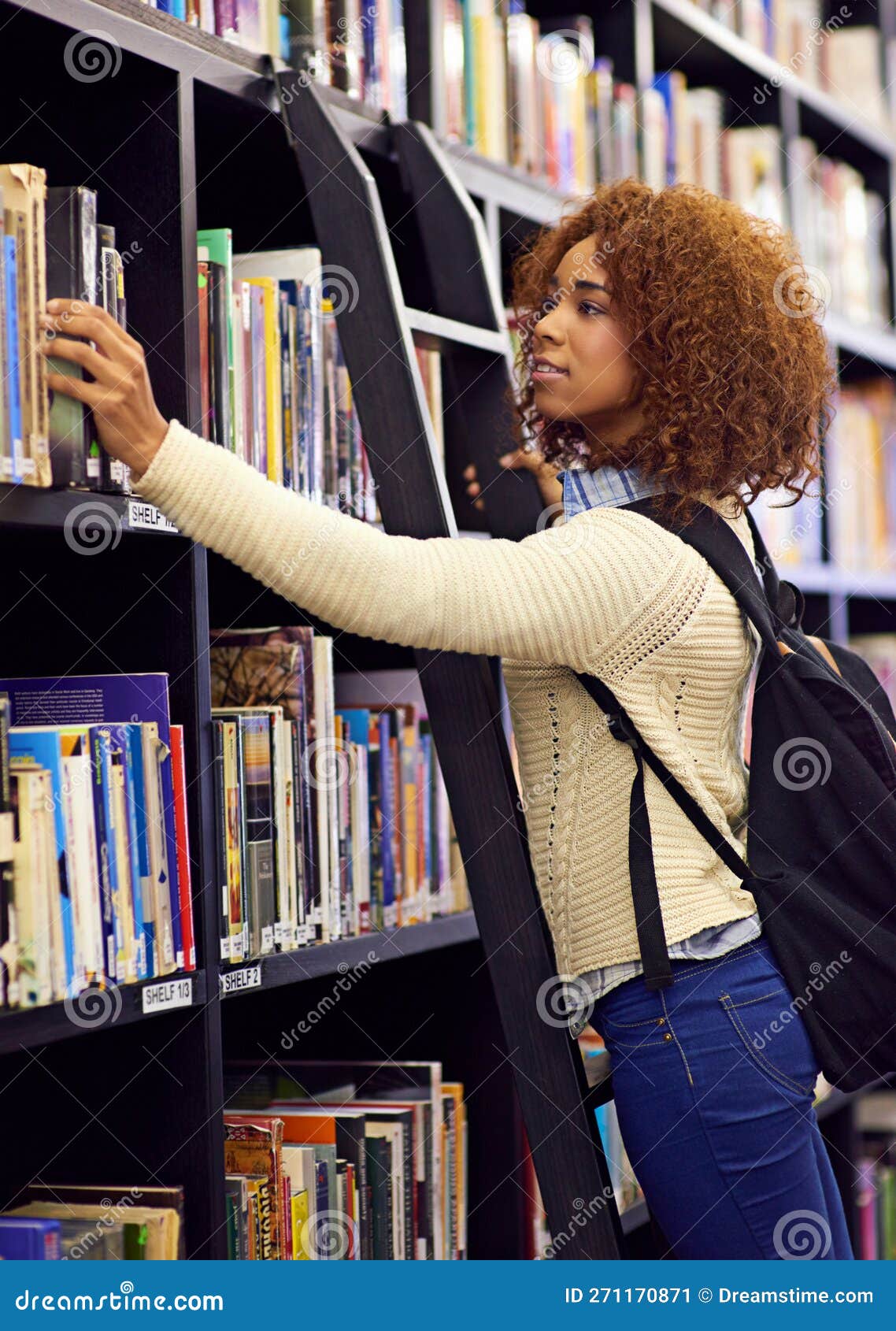 Seeking Knowledge in the Library. a Young Woman Reaching for a Book from a Bookshelf in a ...
