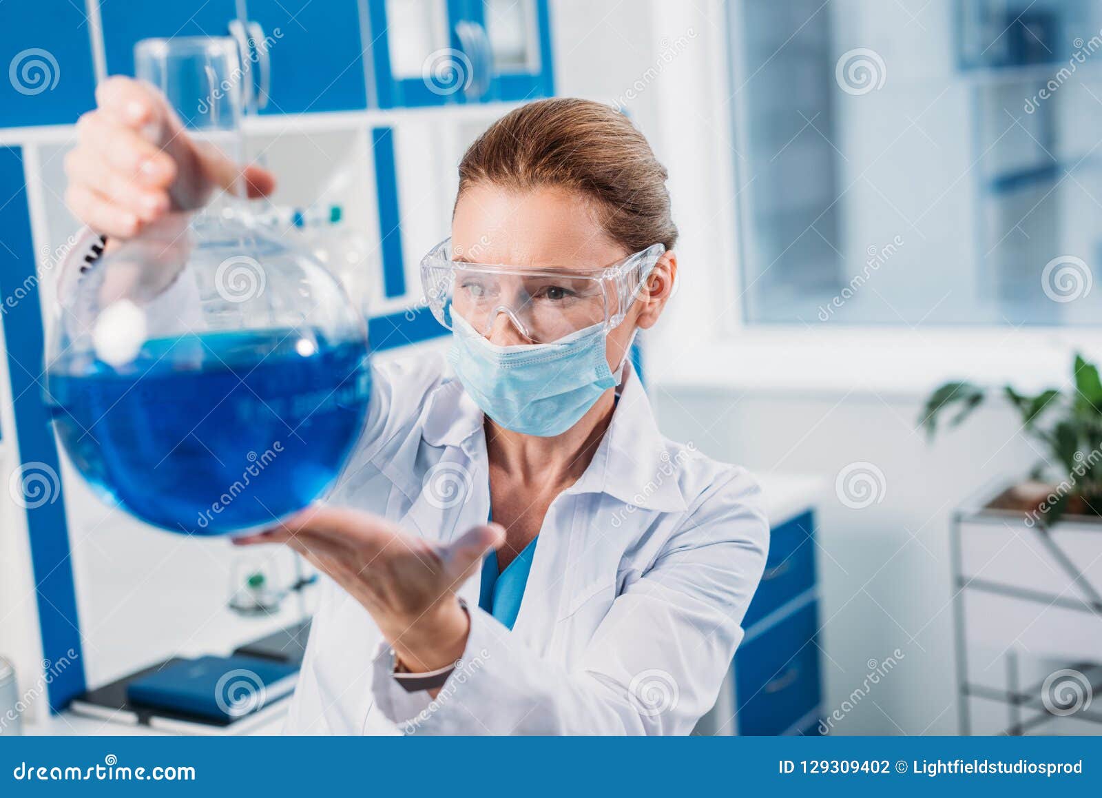 Selective Focus of Female Scientist Looking at Flask in Hands Stock ...