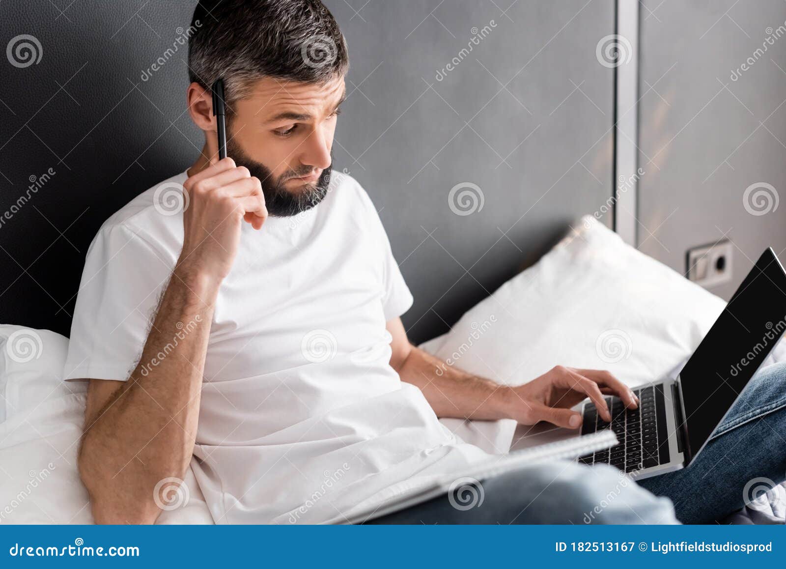 Focus of Handsome Teleworker Working with Laptop Near Notebook on Bed ...