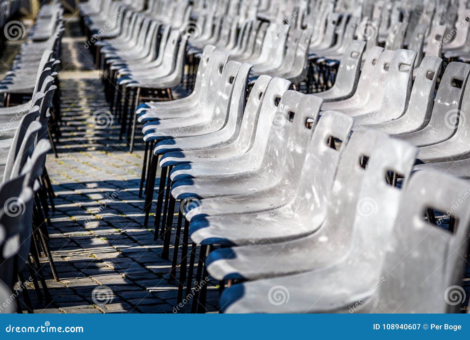 Selective Focus of Many Gray Chairs in Straight Lines on a Cobblestone ...