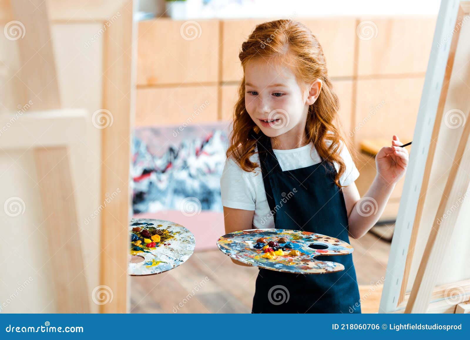 Selective Focus of Redhead Kid Looking at Easel while Holding Palette ...
