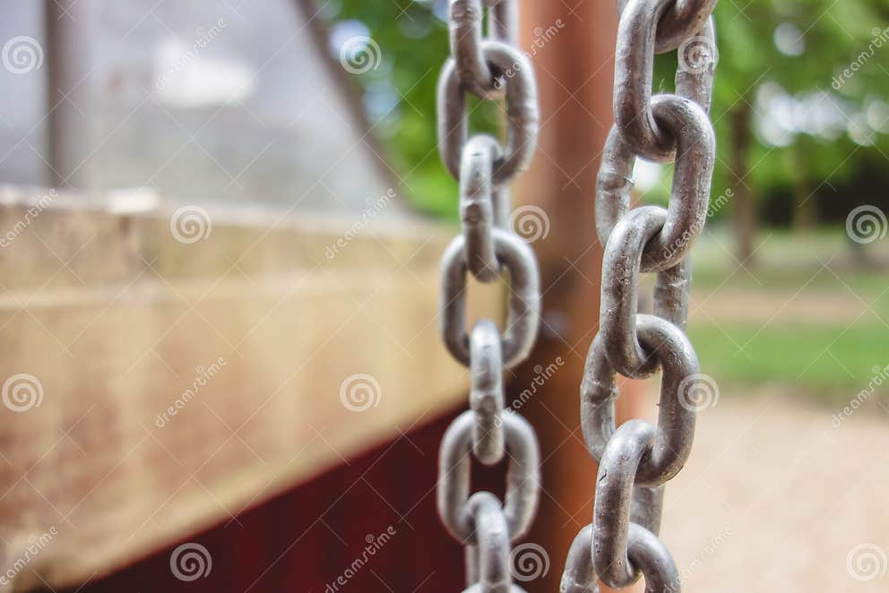 Selective Focus Shot of the Metal Chains of a Swing Set with the Trees ...