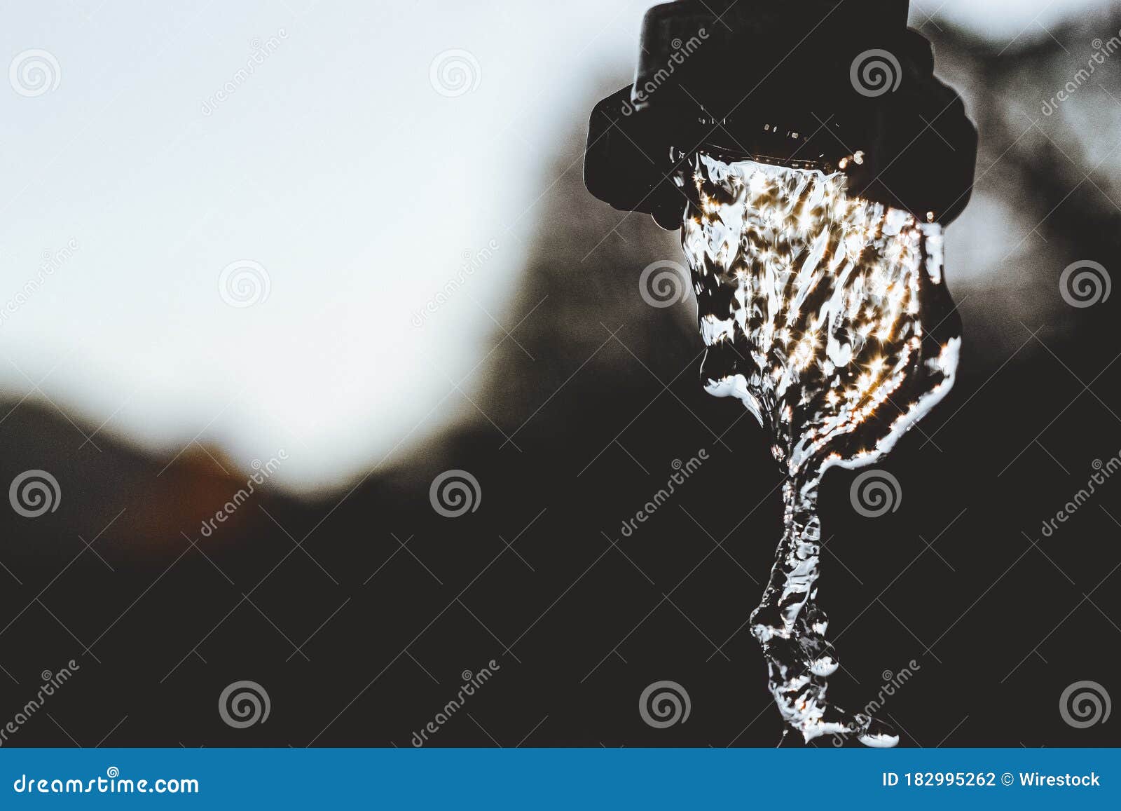 Selective Focus Shot of the Water Dripping from a Faucet with the Trees ...