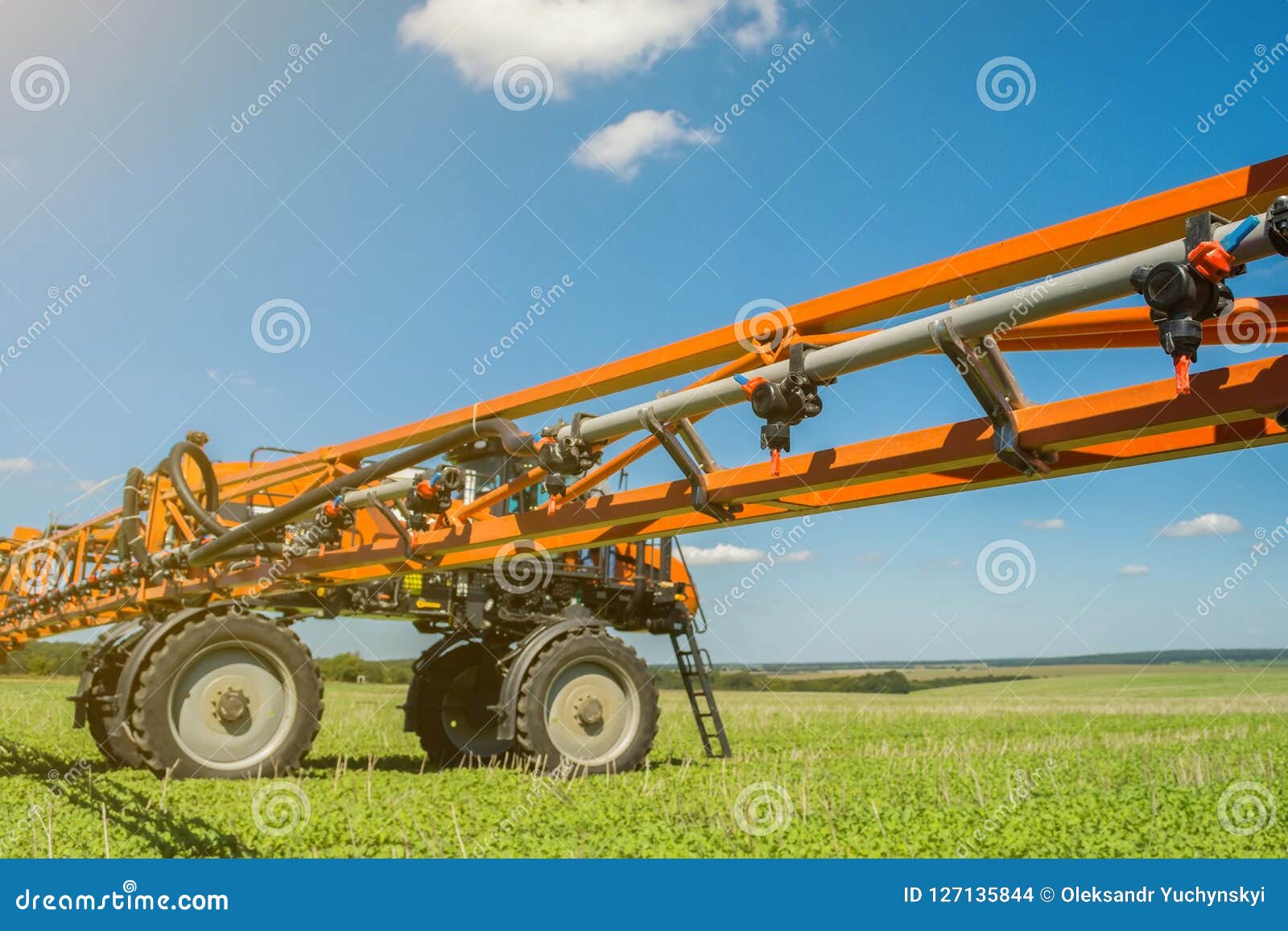 Self-propelled Sprayer Works on a Field Under a Blue Sky with Clouds ...