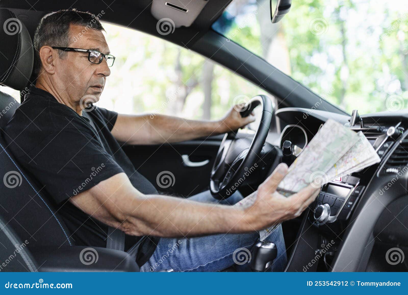 Senior Behind the Steering Wheel Looking at Map for Directions Stock ...