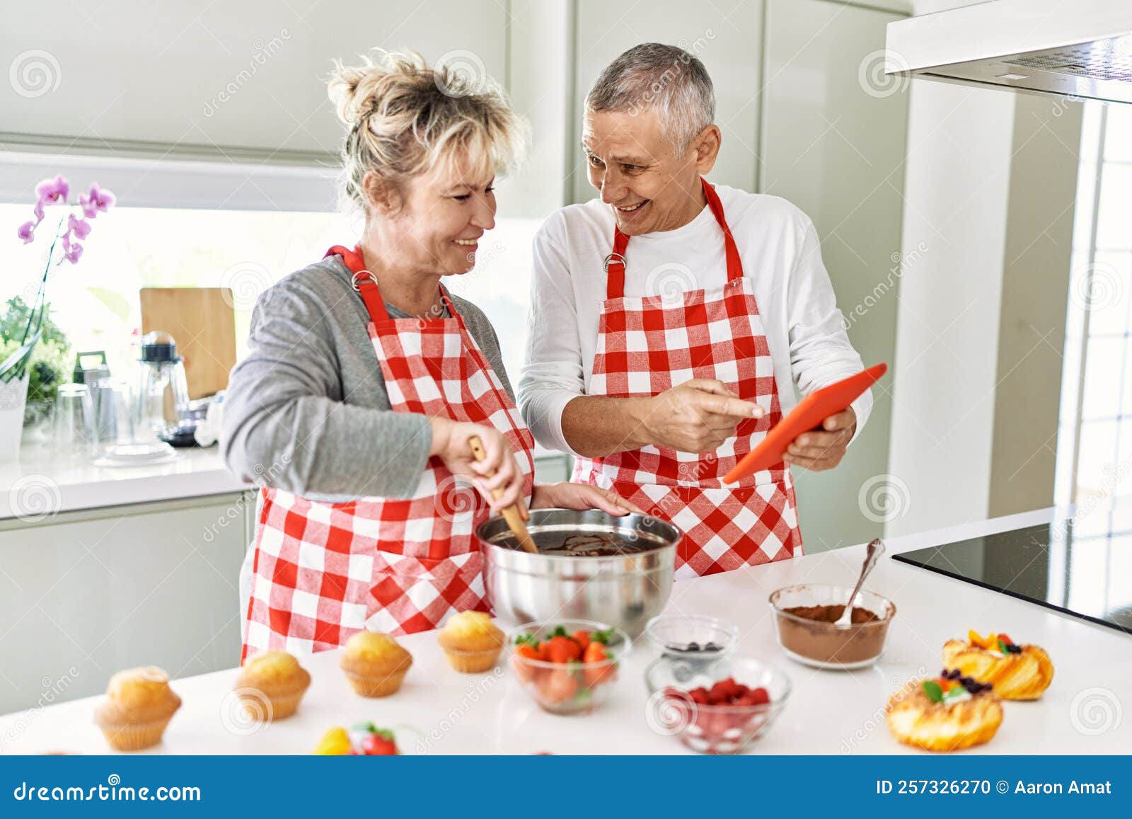 Senior Caucasian Couple Smiling Happy Baking Sweets Using Touchpad at ...