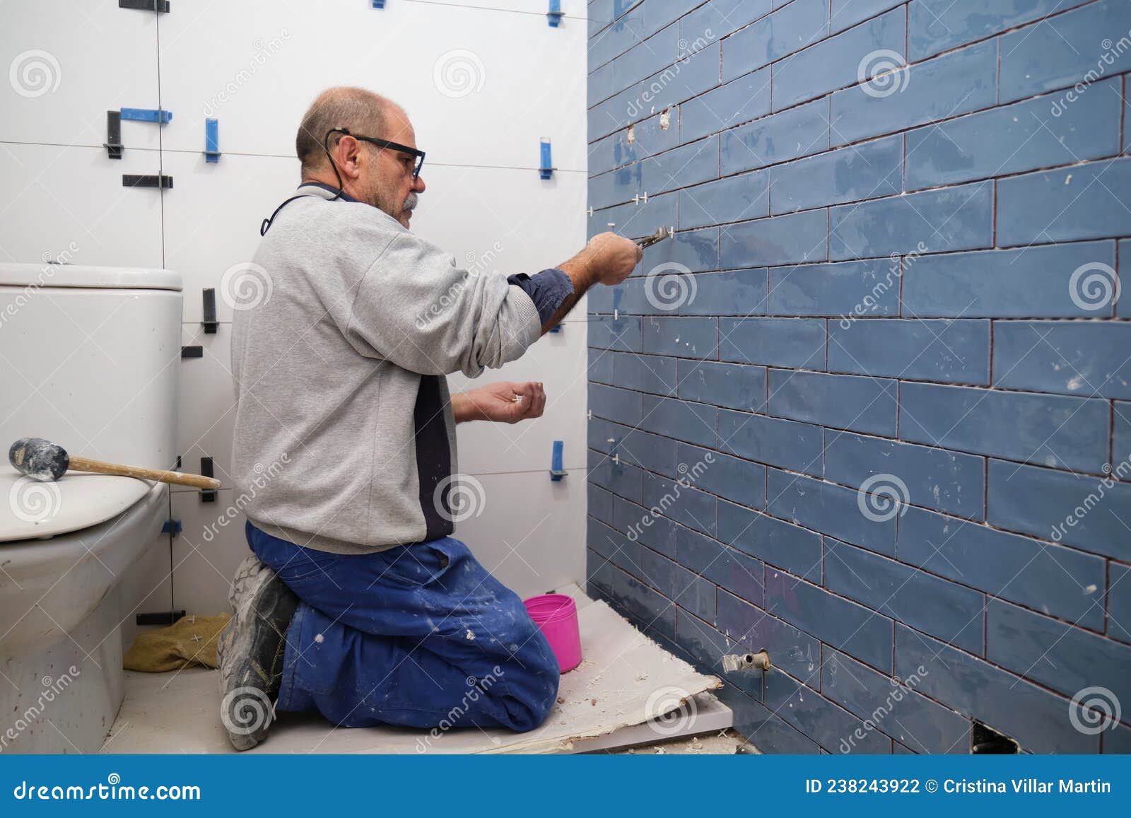 Senior Constructor Worker Removing the Separation between Tiles on the ...