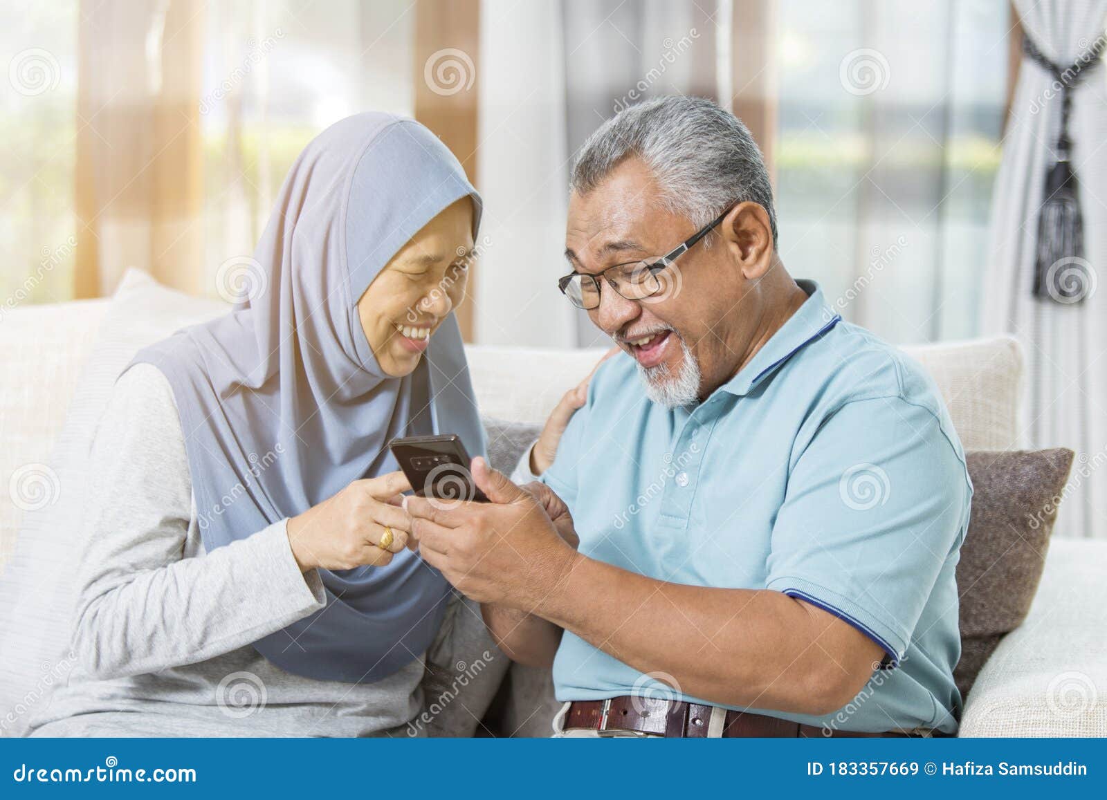 Senior Couple Laughing Together While Holding The Smartphone Stock