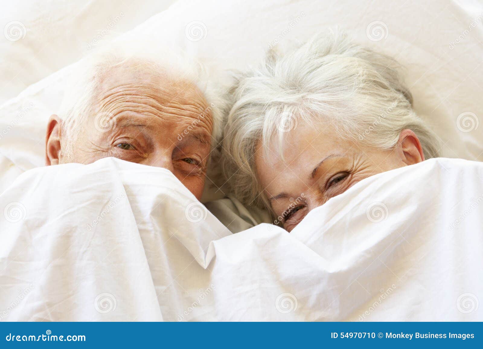 Senior Couple Relaxing in Bed Hiding Under Sheets Stock Photo - Image ...
