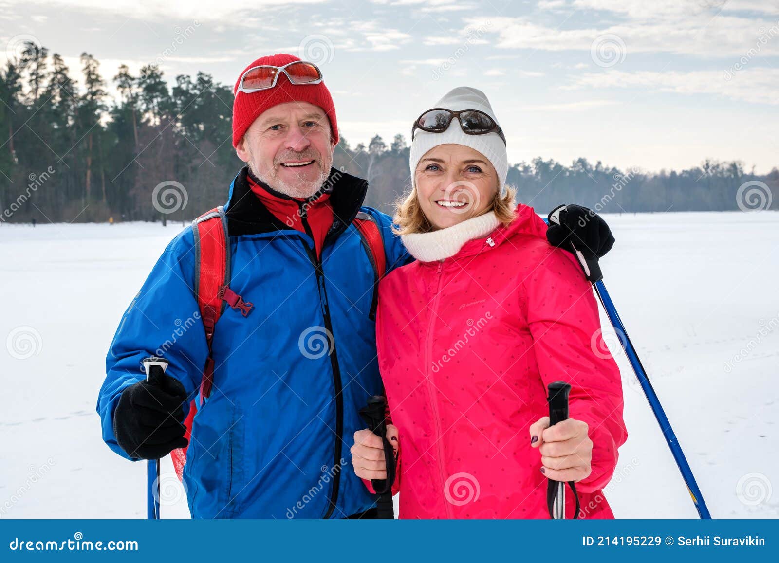 Elderly Couple Walking With Nordic Walking Poles In Snowy Winter Park