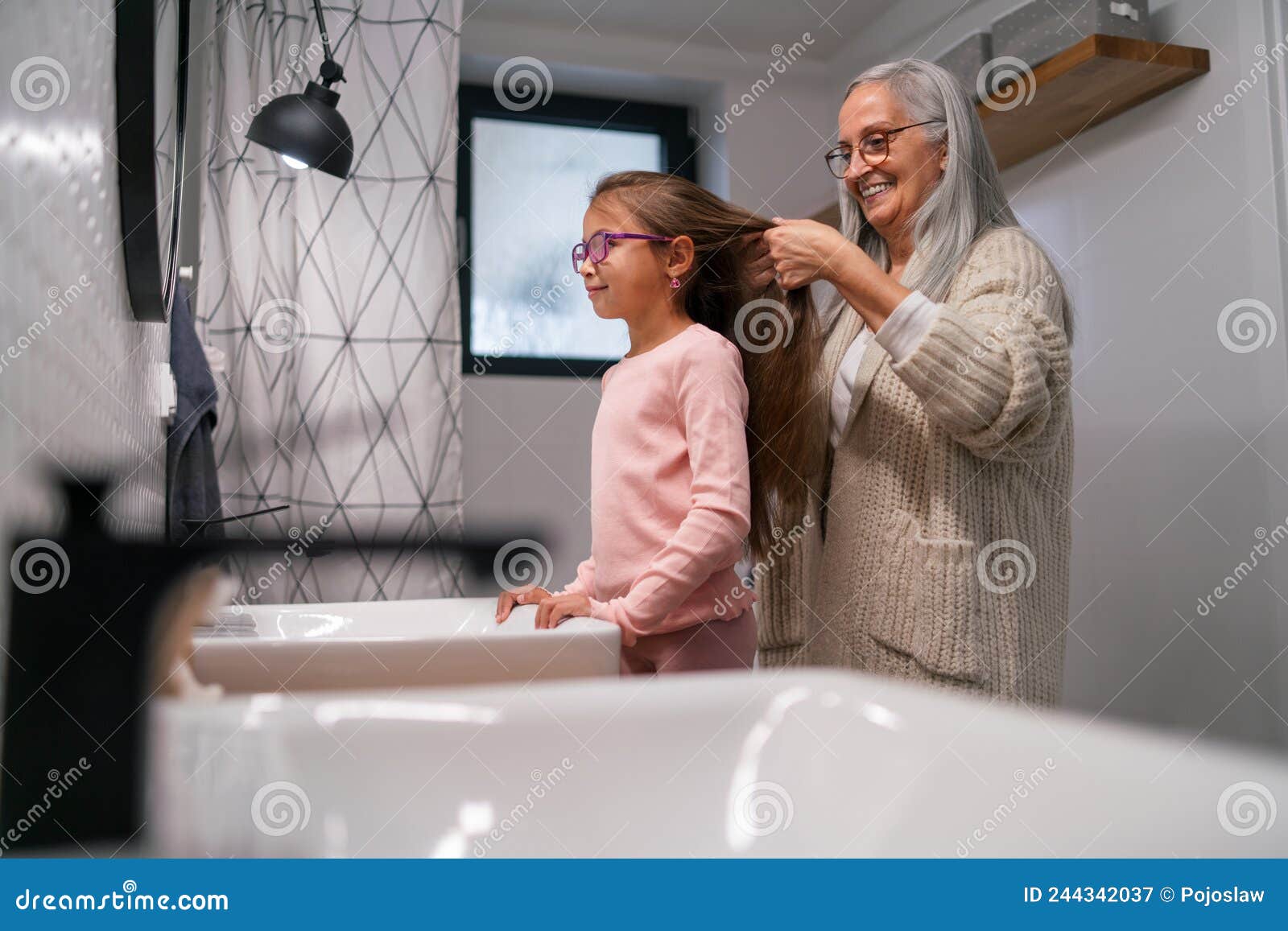 Senior Grandmother And Granddaughter Standing Indoors In Bathroom