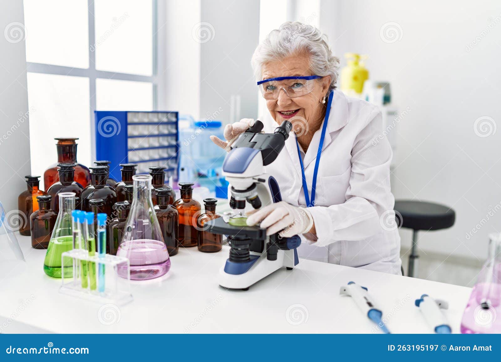 Senior Grey Haired Woman Wearing Scientist Uniform Using Microscope At