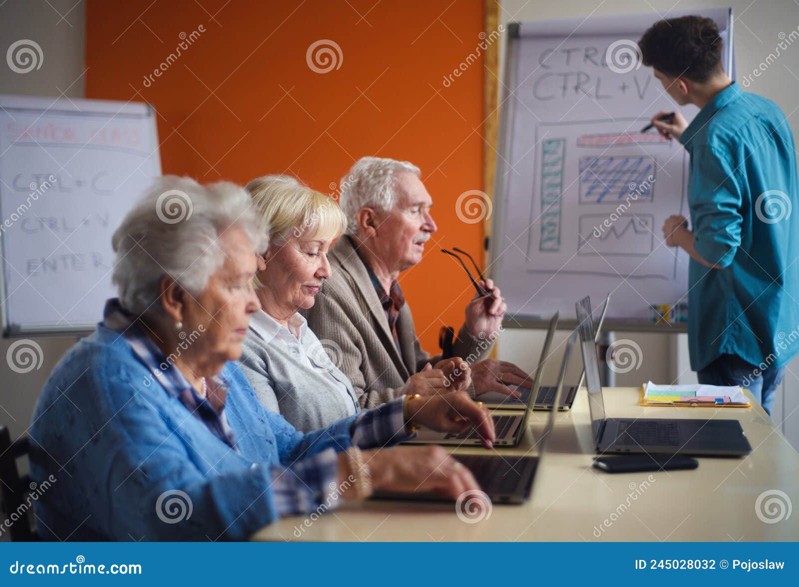 Senior Group in Retirement Home with Young Instructor Learning Together ...