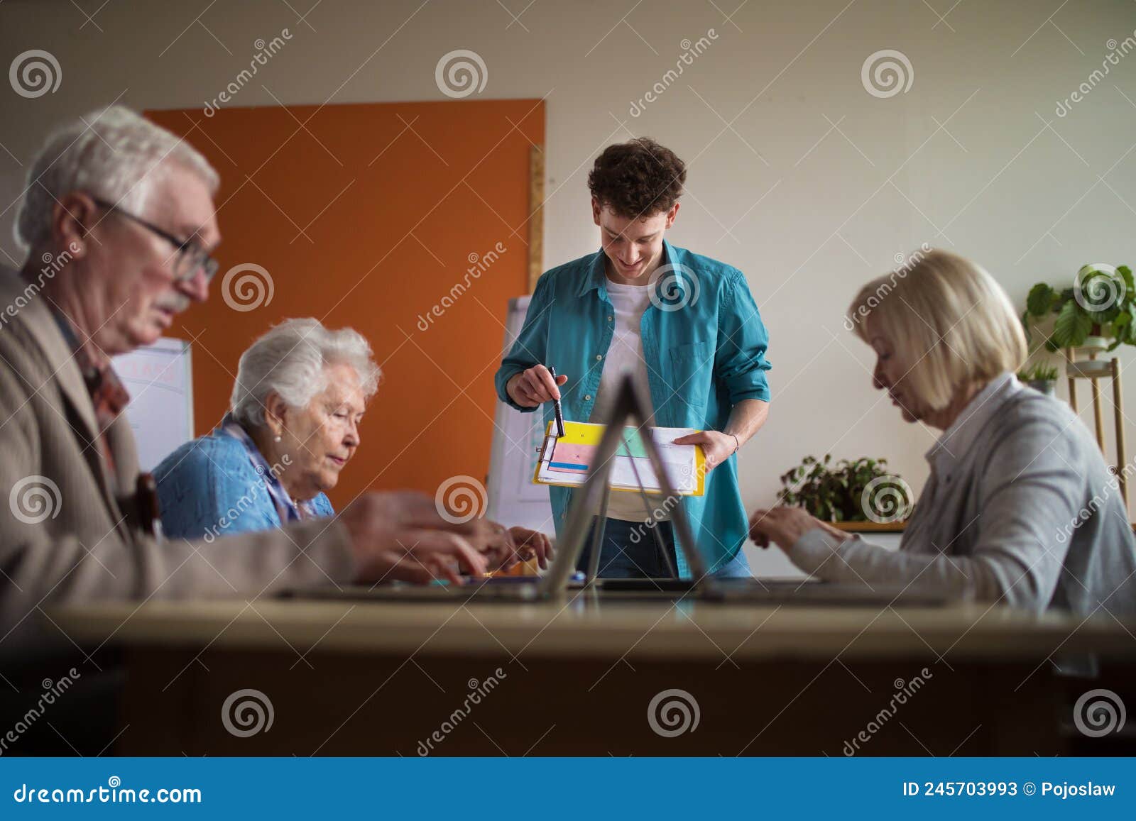 Senior Group in Retirement Home with Young Instructor Learning Together ...