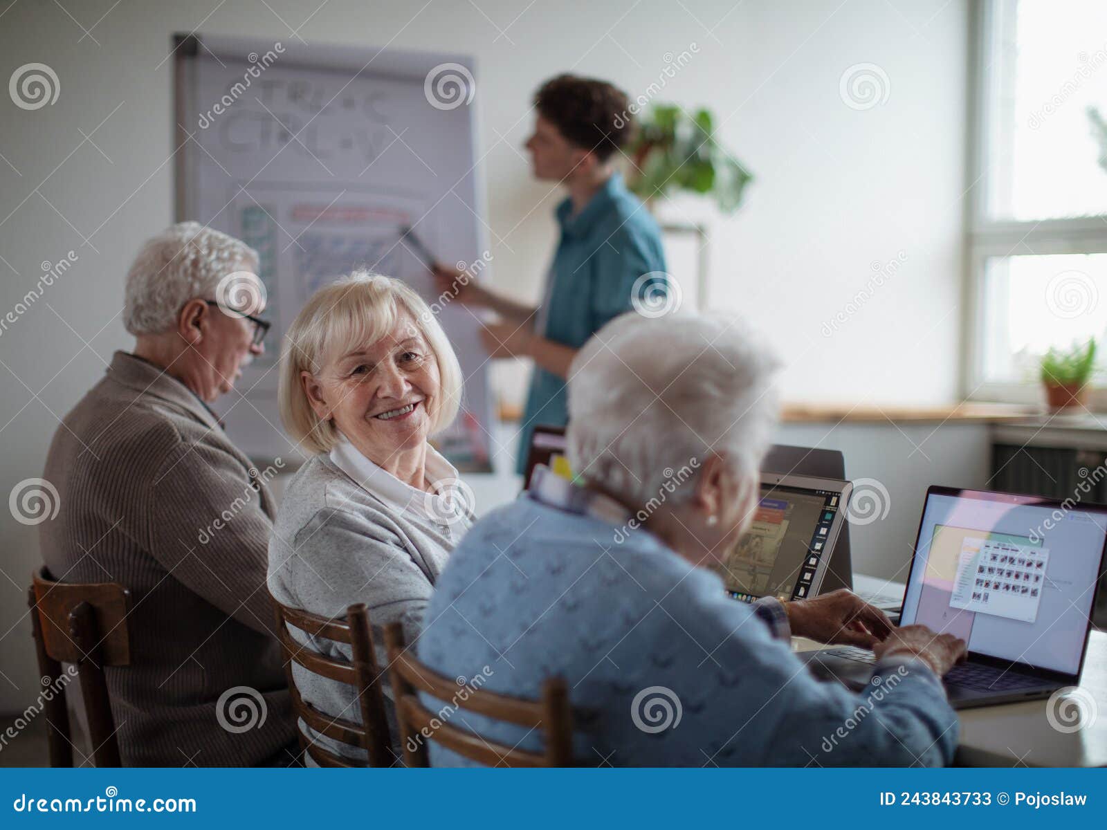 Senior Group in Retirement Home with Young Instructor Learning Together ...