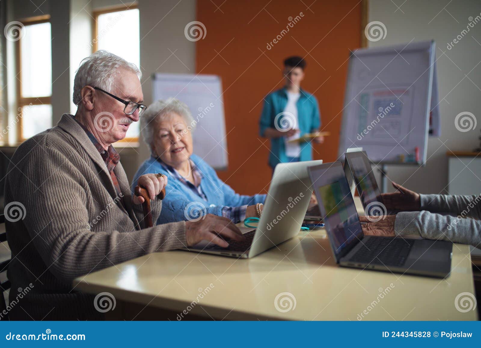 Senior Group in Retirement Home with Young Instructor Learning Together ...