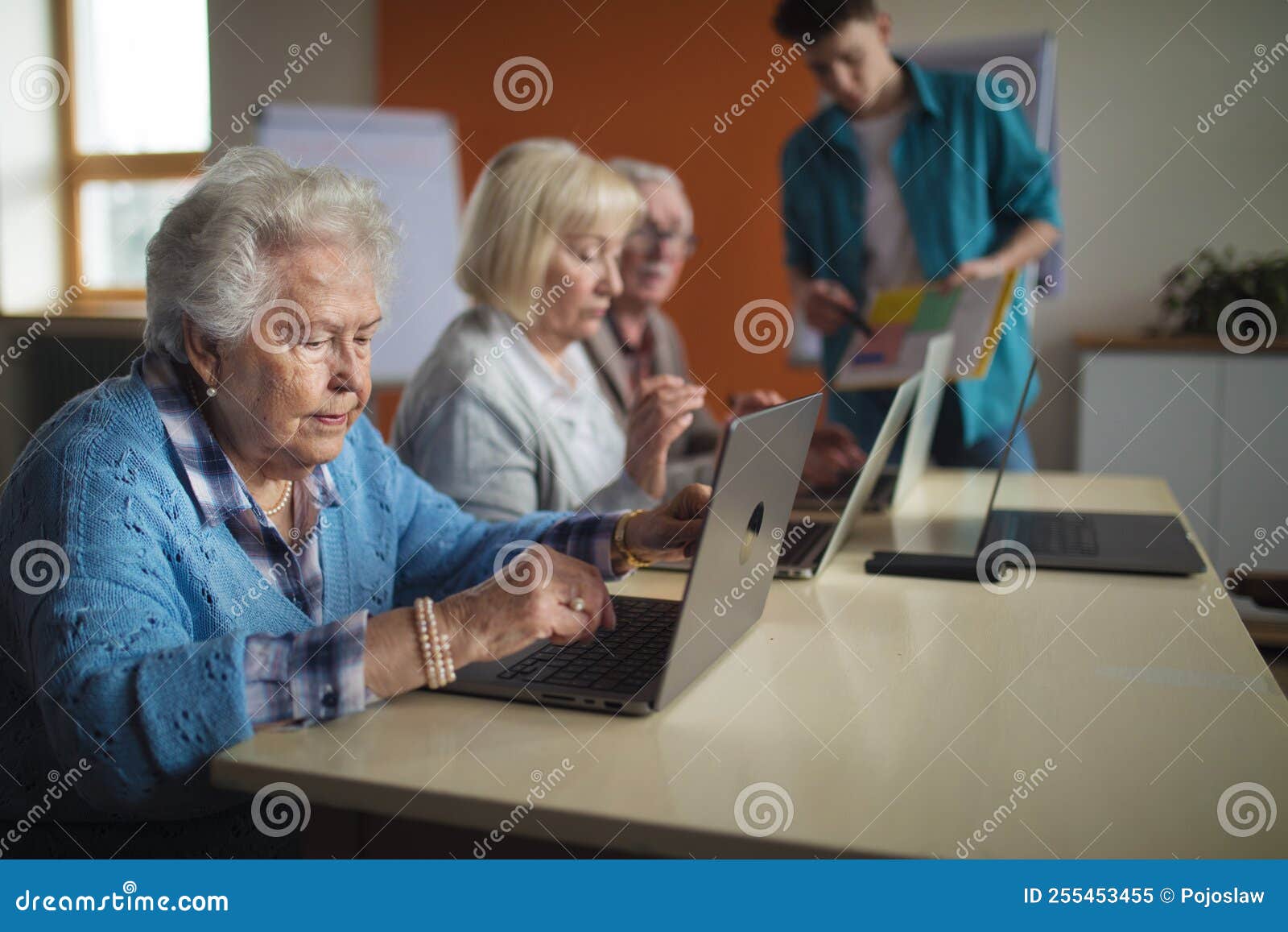 Senior Group in Retirement Home with Young Instructor Learning Together ...