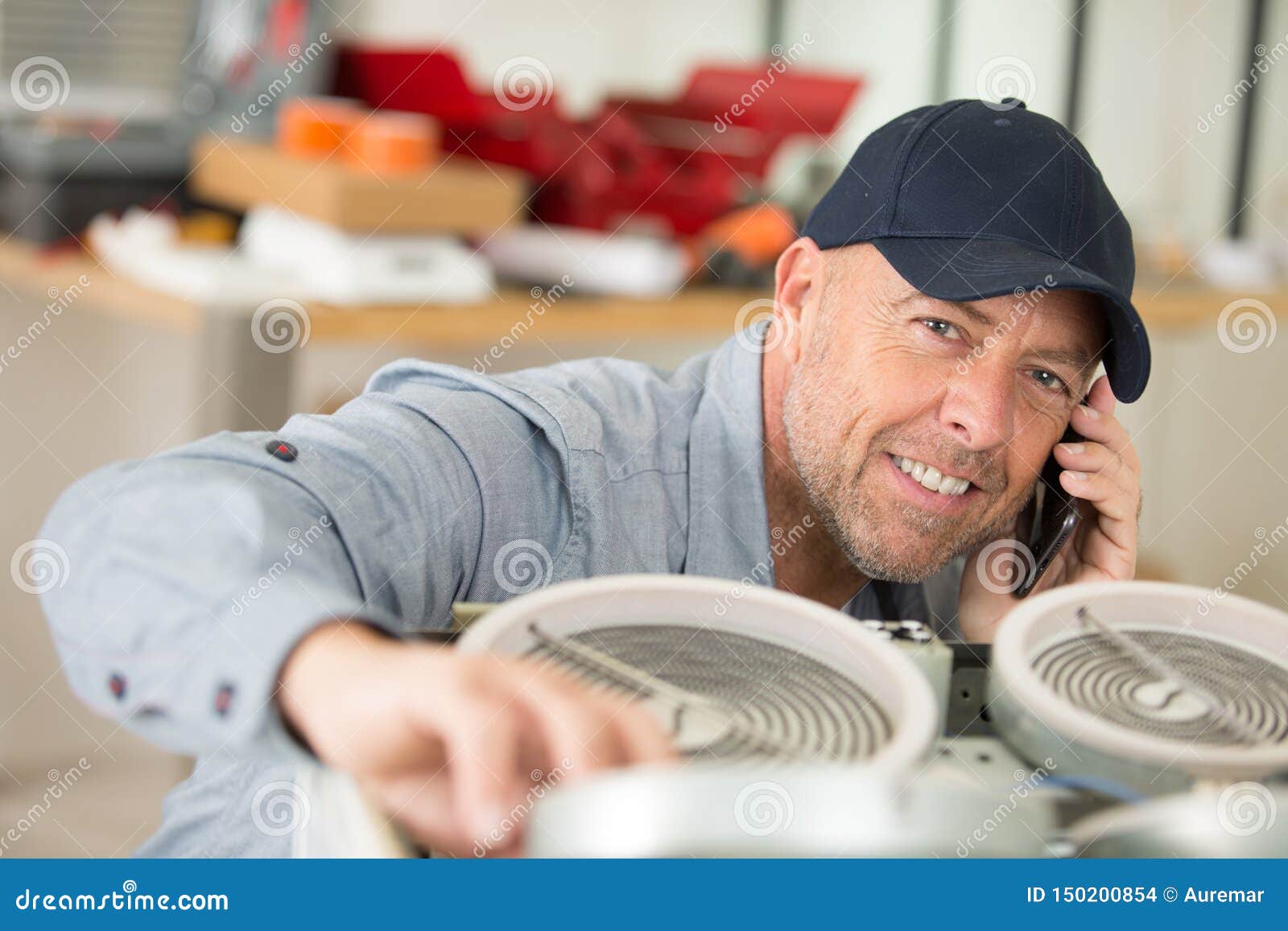 Senior Handyman Taking Smartphone Call while Working on Appliance Stock ...