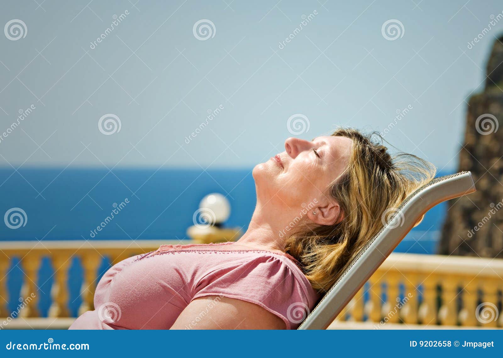 Senior Lady Sunbathing Against Coastal Backdrop Stock Photo - Image of ...