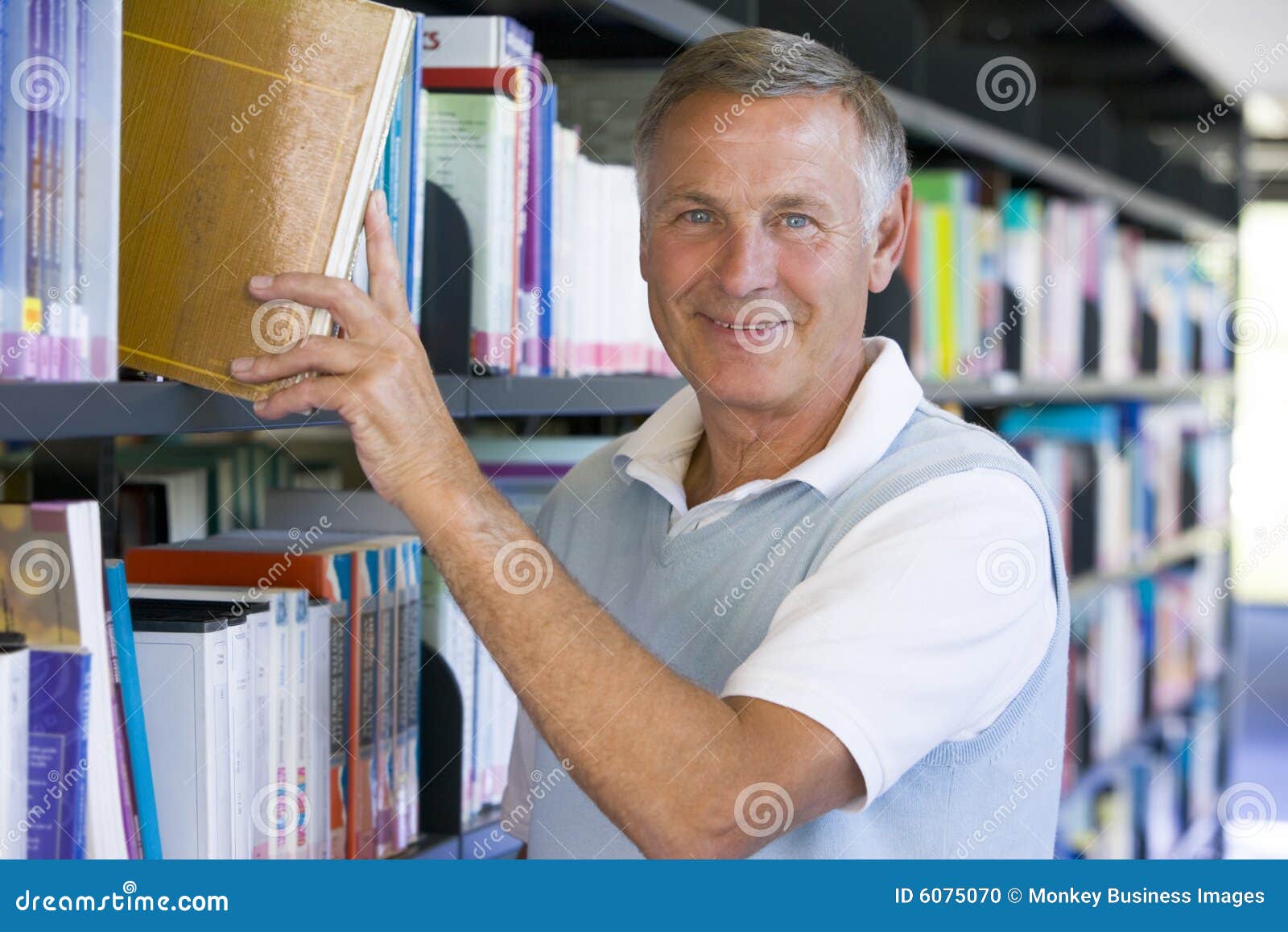 Senior Man Pulling a Library Book Off Shelf Stock Photo - Image of ...