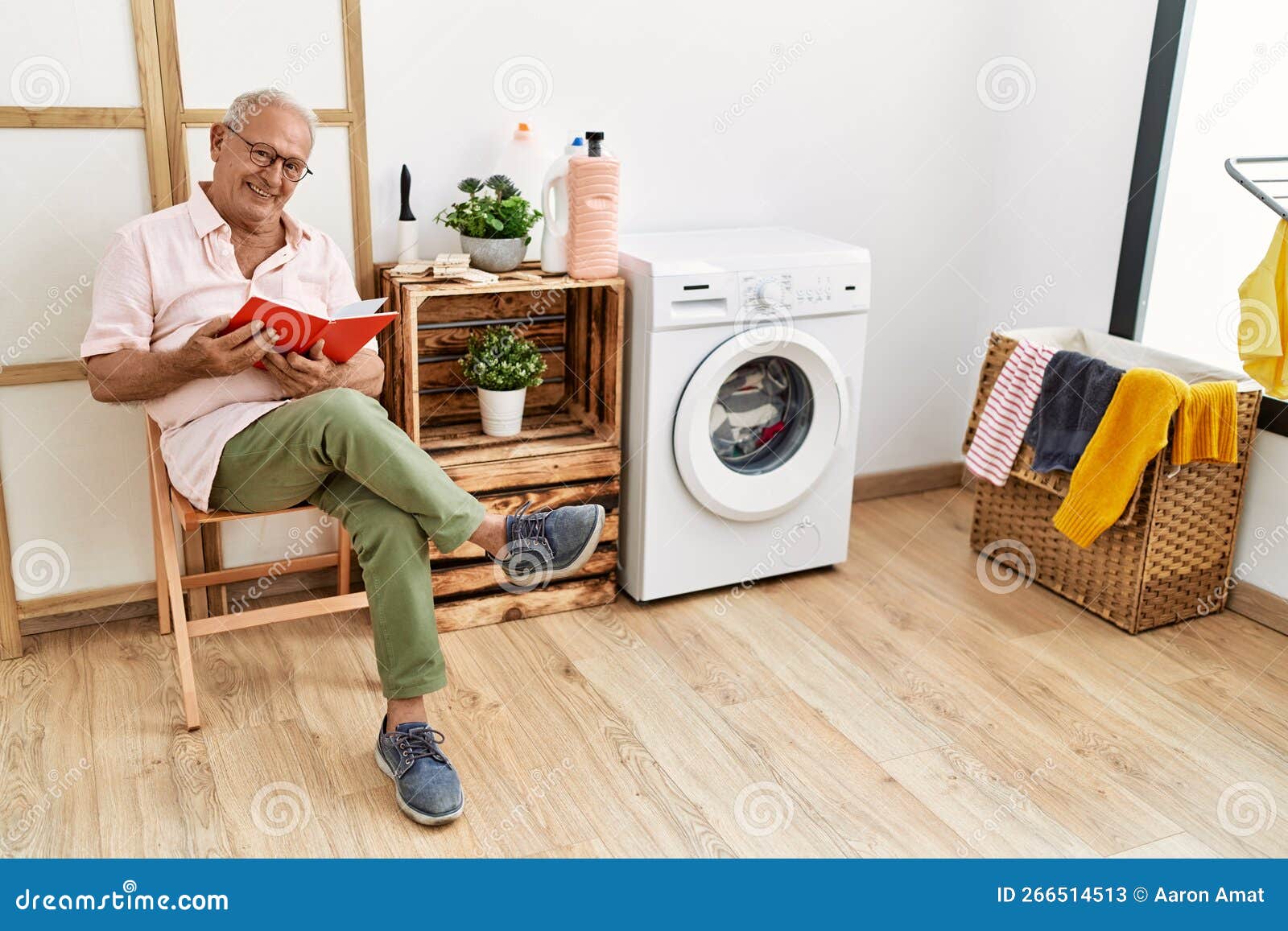 Senior Man Reading Book Waiting for Washing Machine at Laundry Room ...