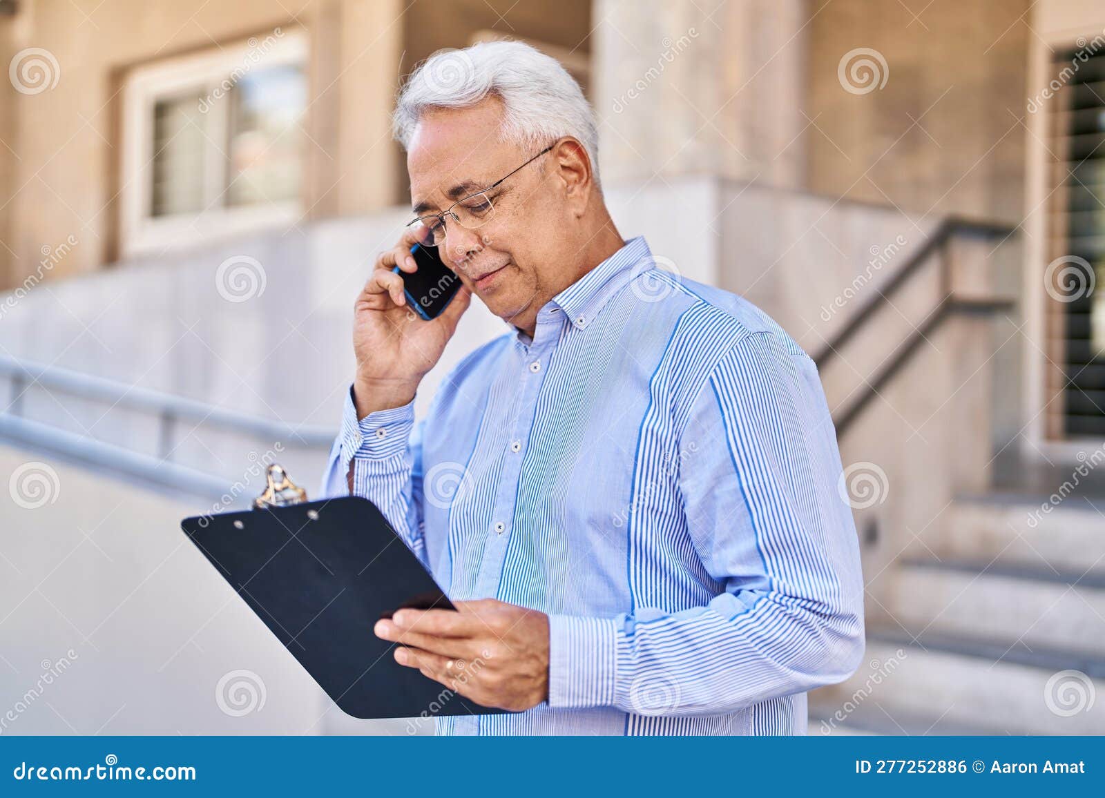 Senior Man Talking on the Smartphone Reading Document at Street Stock ...