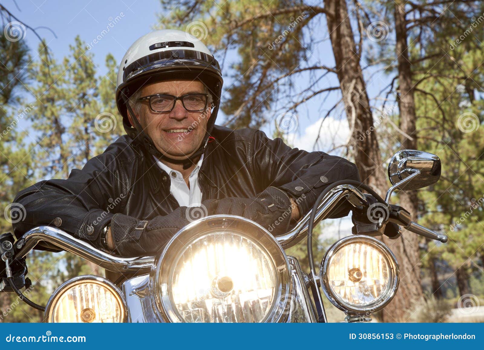 Senior Man Wearing Helmet Leaning on Motorcycle Handlebars in Forest ...