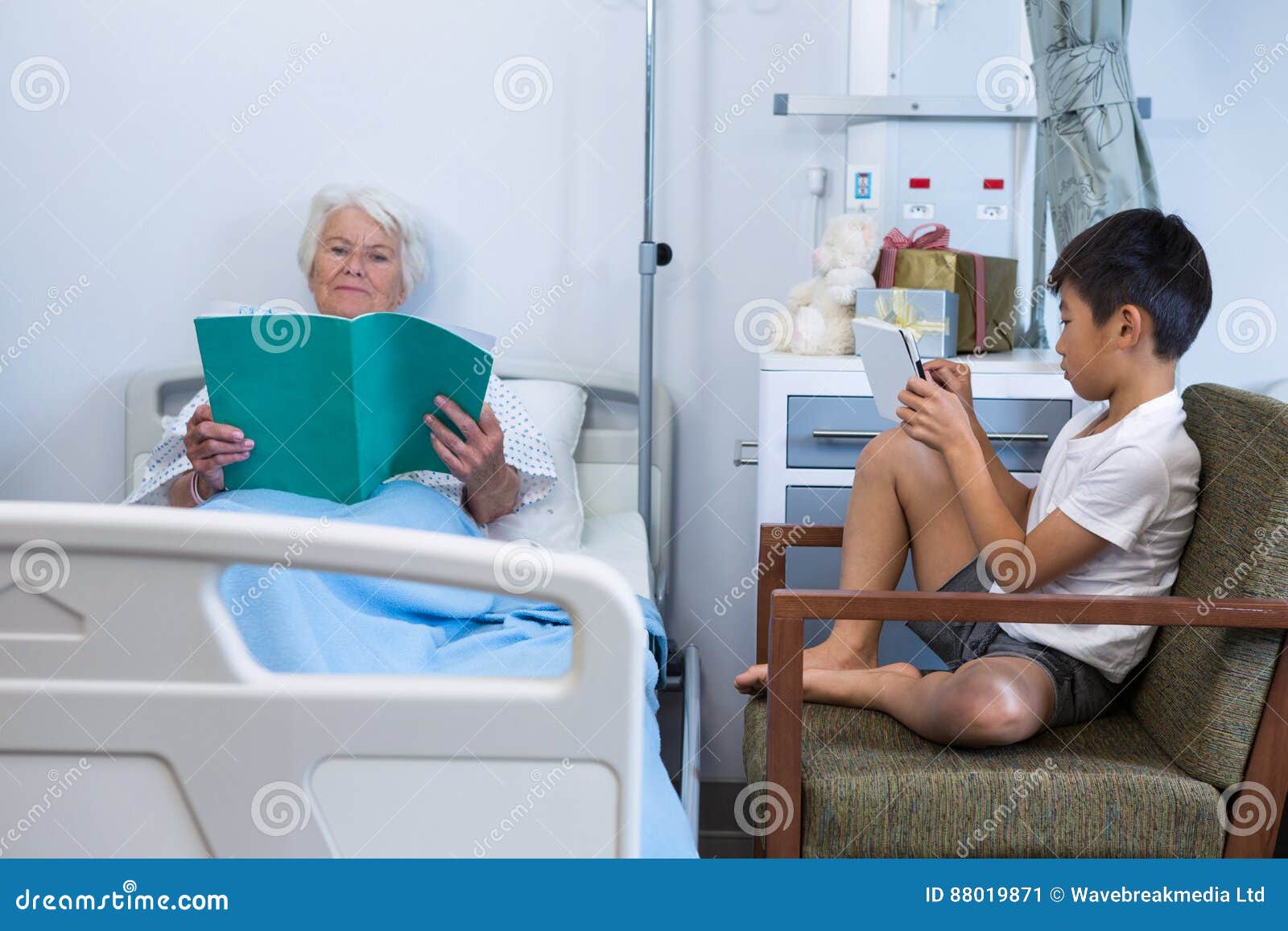 Senior Patient Reading a Book while Boy Using Digital Tablet Stock ...