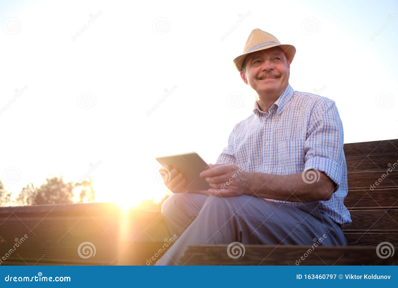Senior Spanish Man Using Tablet in Park Sitting on Bench on Sunset ...