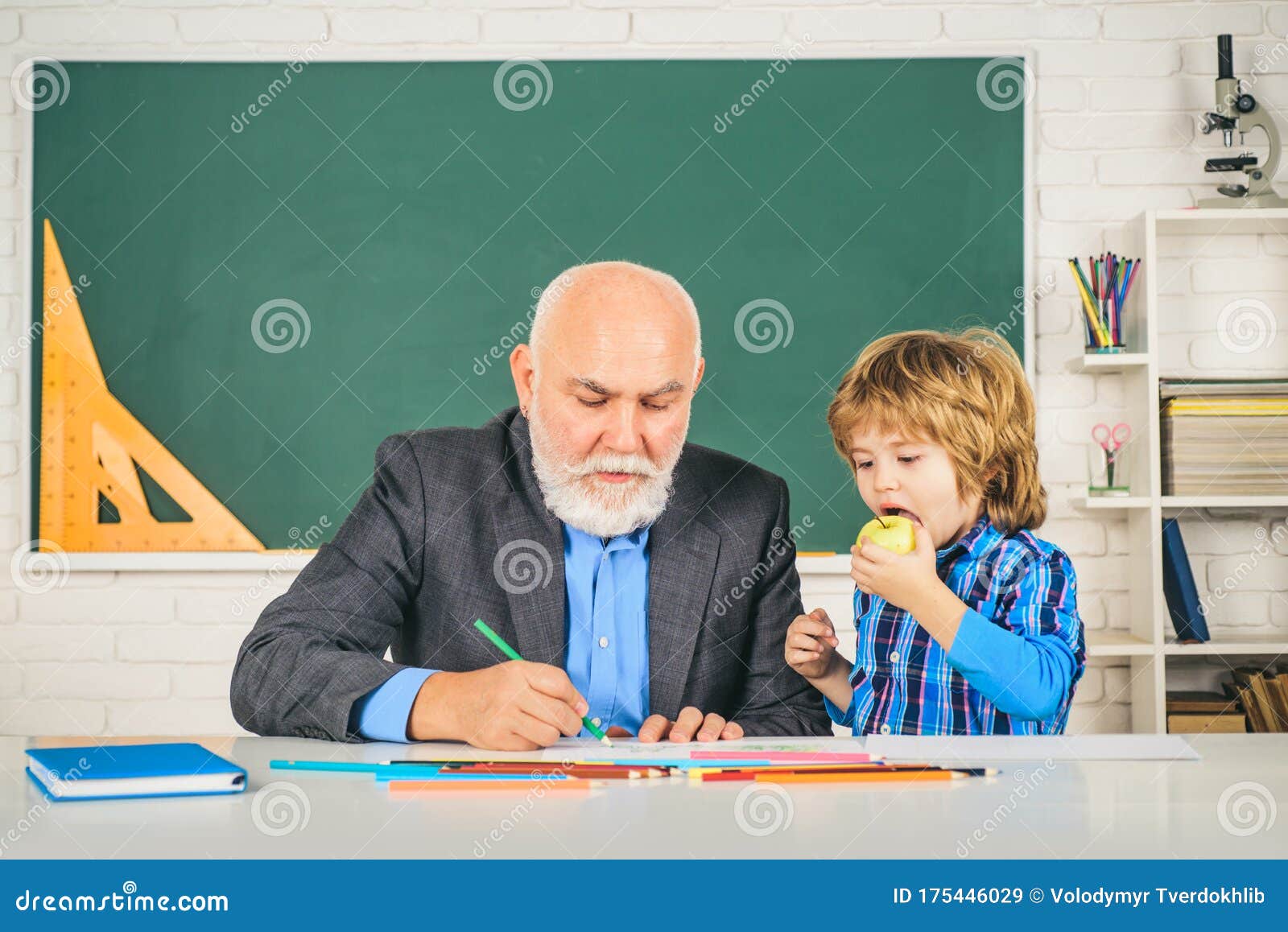 Senior Teacher in Classroom with Elementary School Kid. Professor and ...