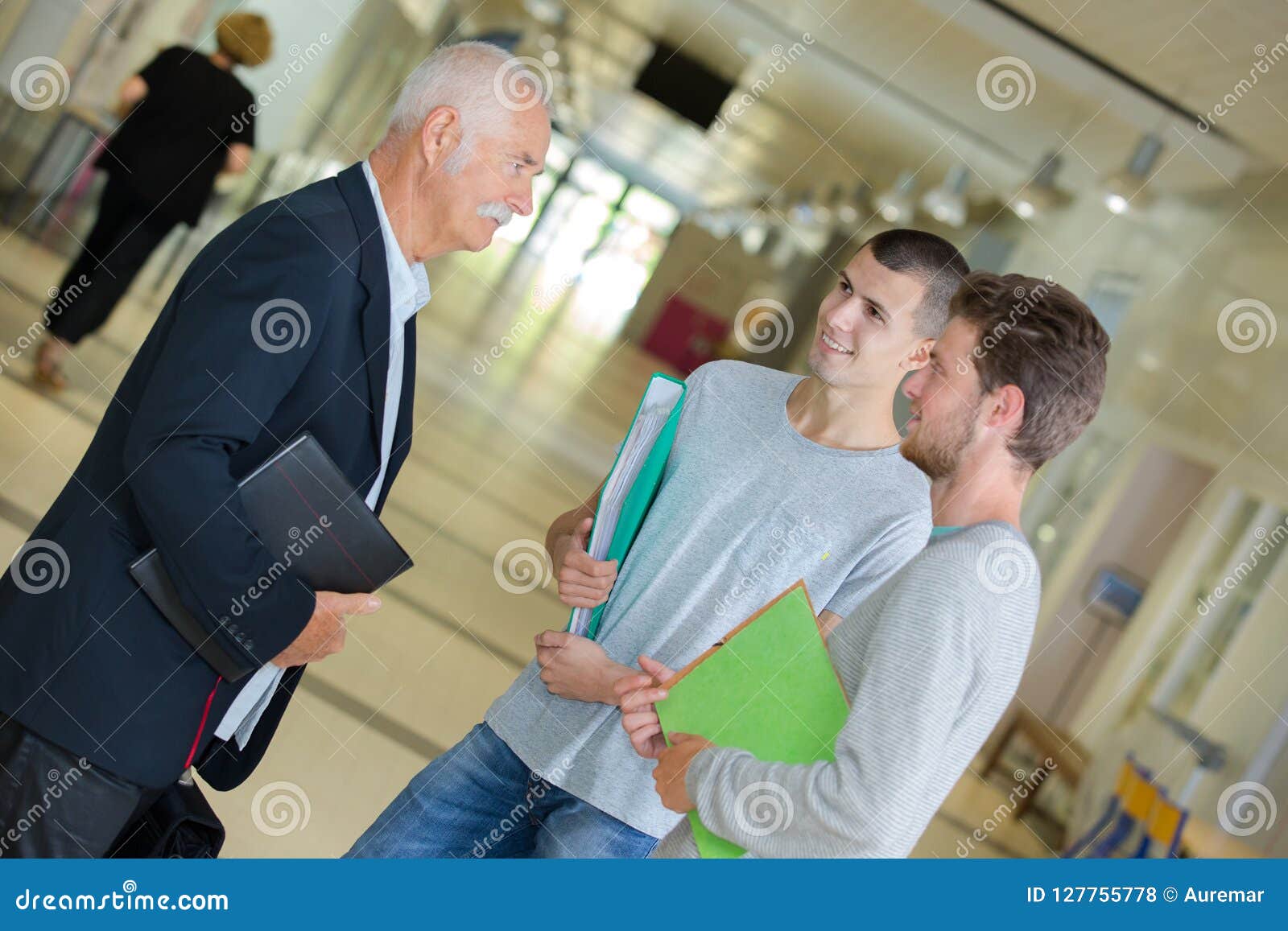 Senior Teacher Discussing with Students in University Corridor Stock ...