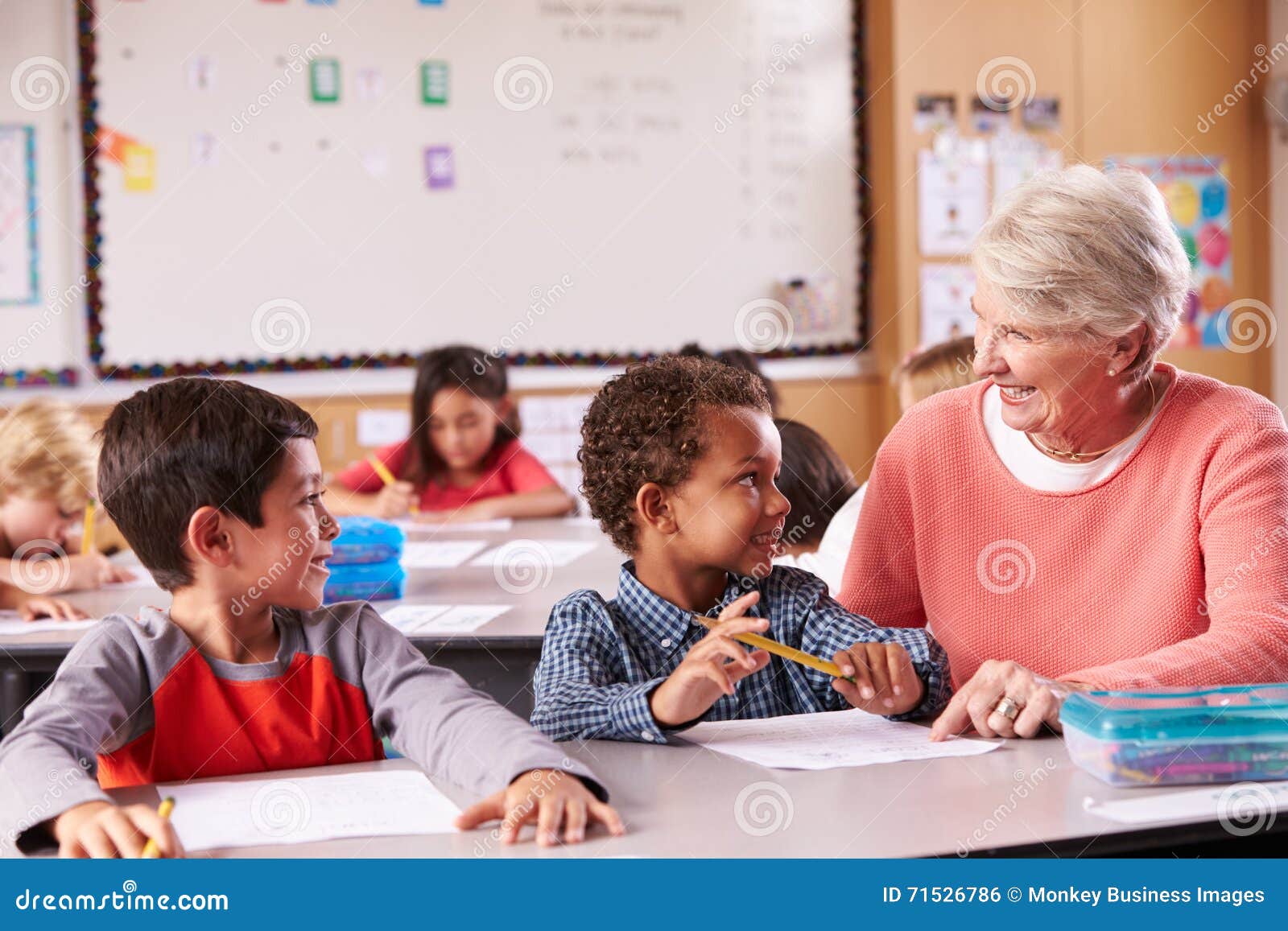 Senior Teacher Sitting with Elementary School Kids in Class Stock Photo ...