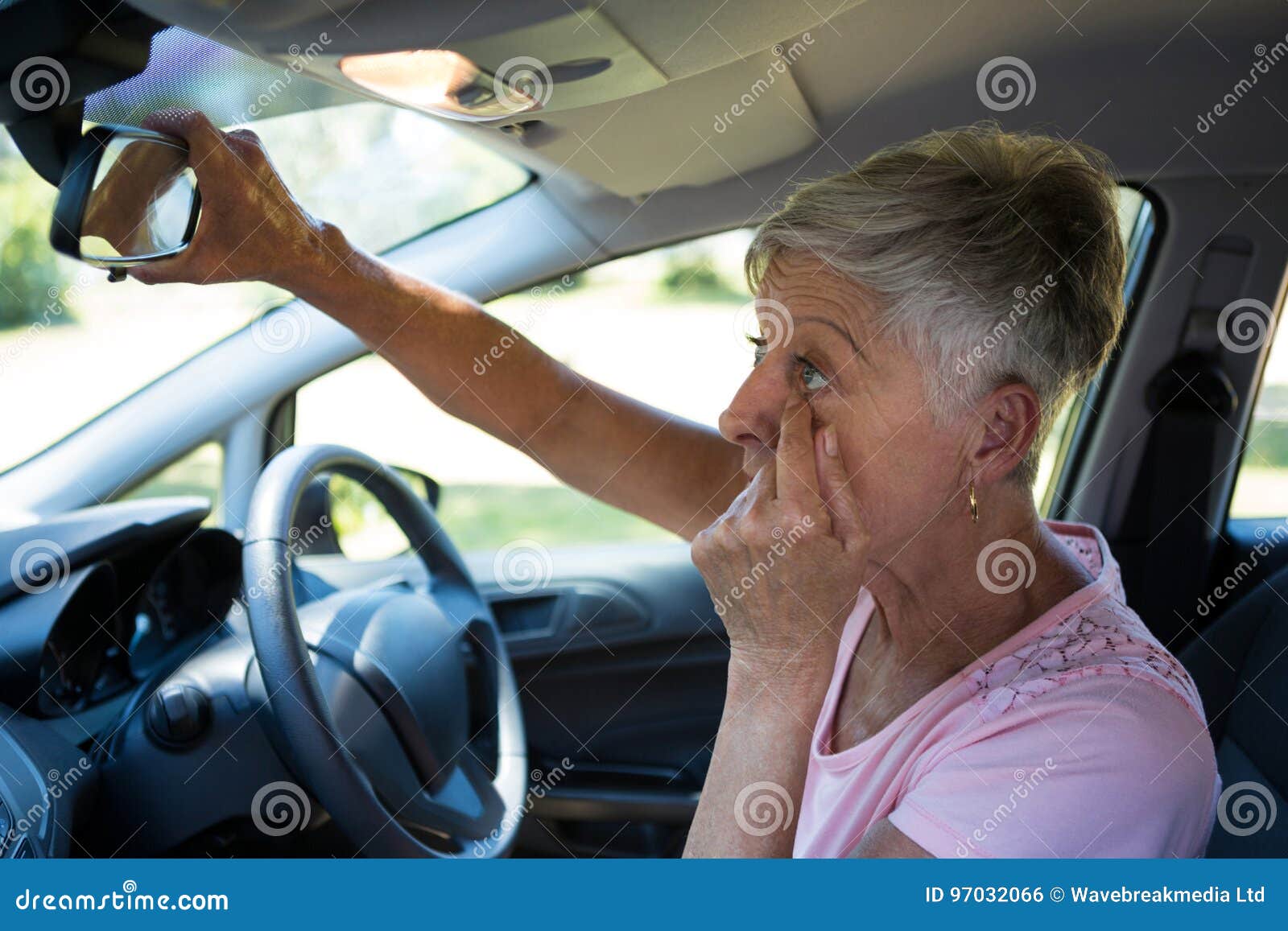 Senior Woman Looking into Rear View Mirror while Driving a Car Stock ...
