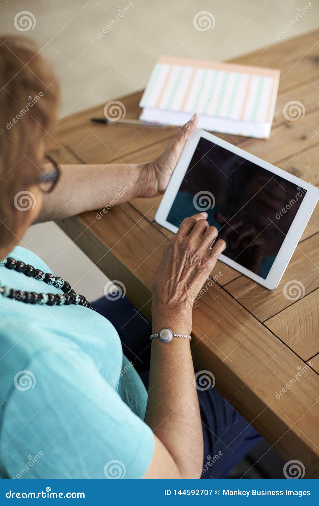 Senior Woman Sitting at Table Using Tablet Computer, Elevated Over ...