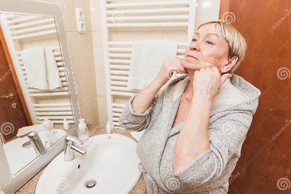 Senior Woman Touching Her Soft Face Skin And Does Massage Looking In