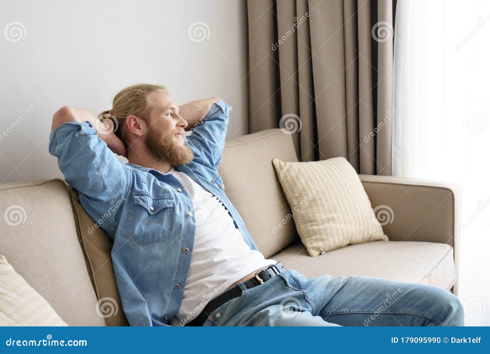 Smiling Relaxed Young Man Lounge On Comfortable Sofa Looking Away