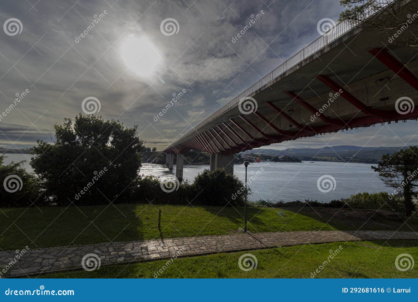 A Serene Walkway Over Water: the Red and White Bridge in a Green Park ...