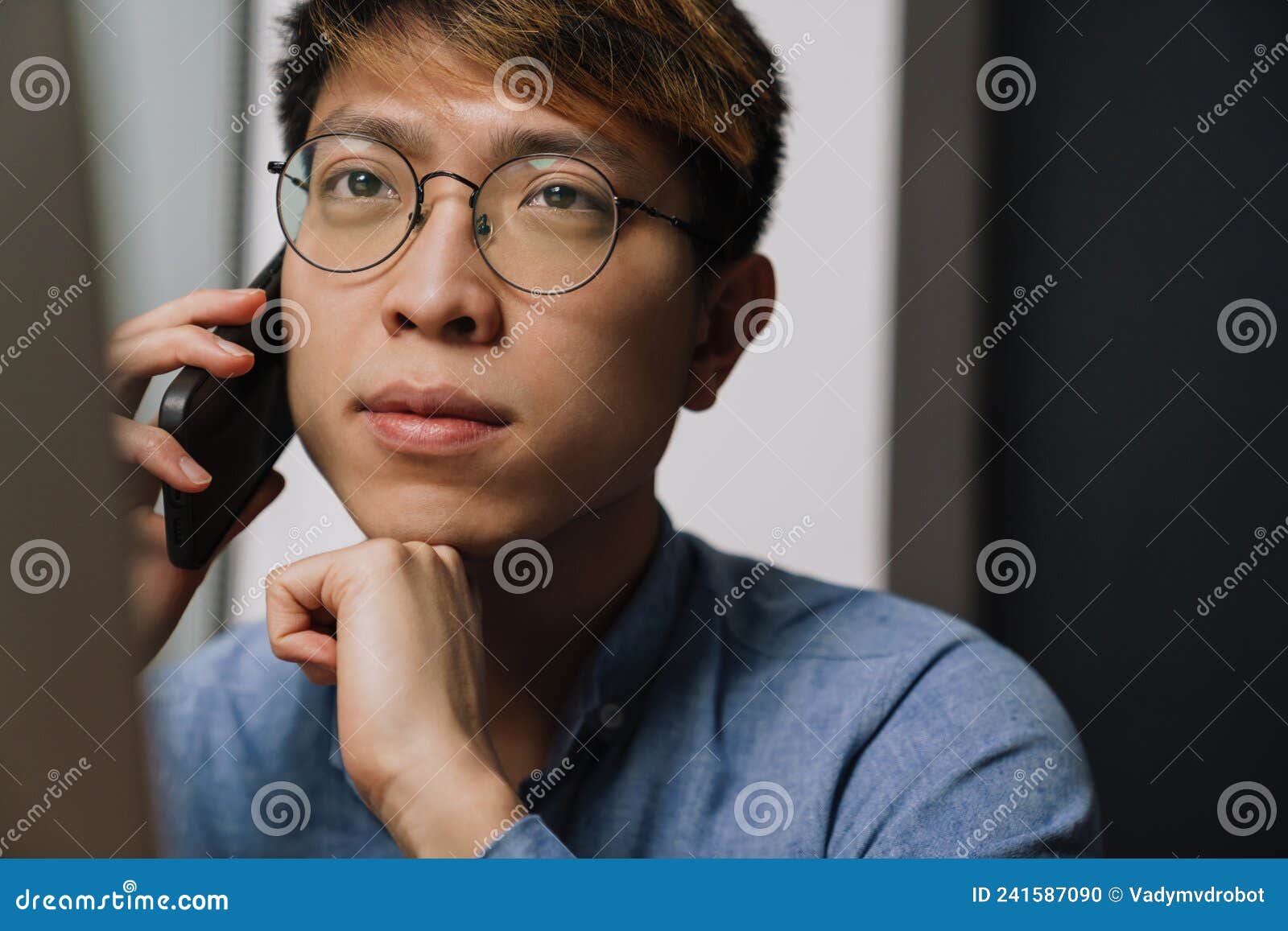 Serious Asian Guy Talking on Cellphone while Working with Laptop Stock ...
