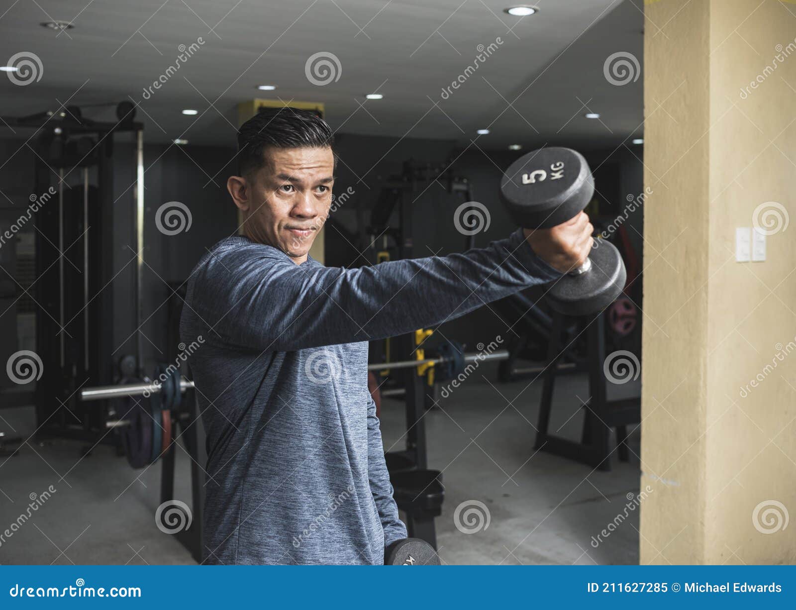 A Serious and Athletic Man Does Reverse Alternating Dumbbell Raises ...