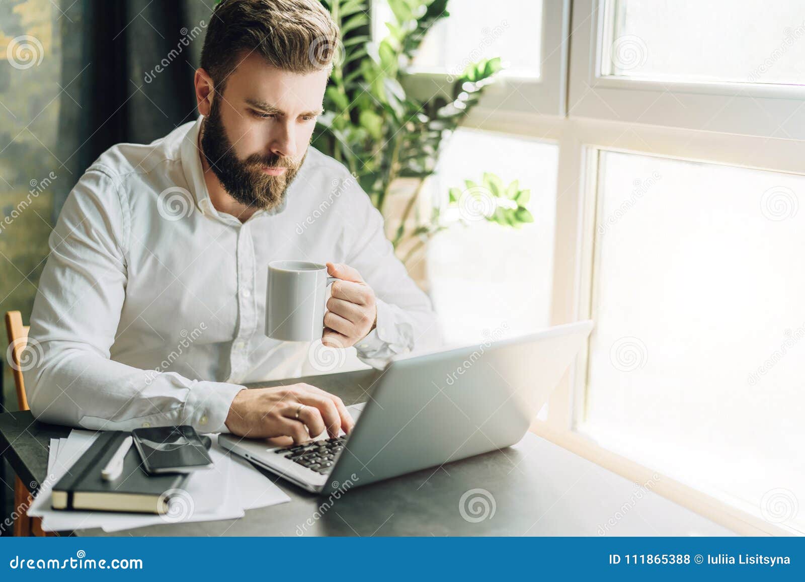 Serious Bearded Businessman is Sitting at Table, Working on Computer ...