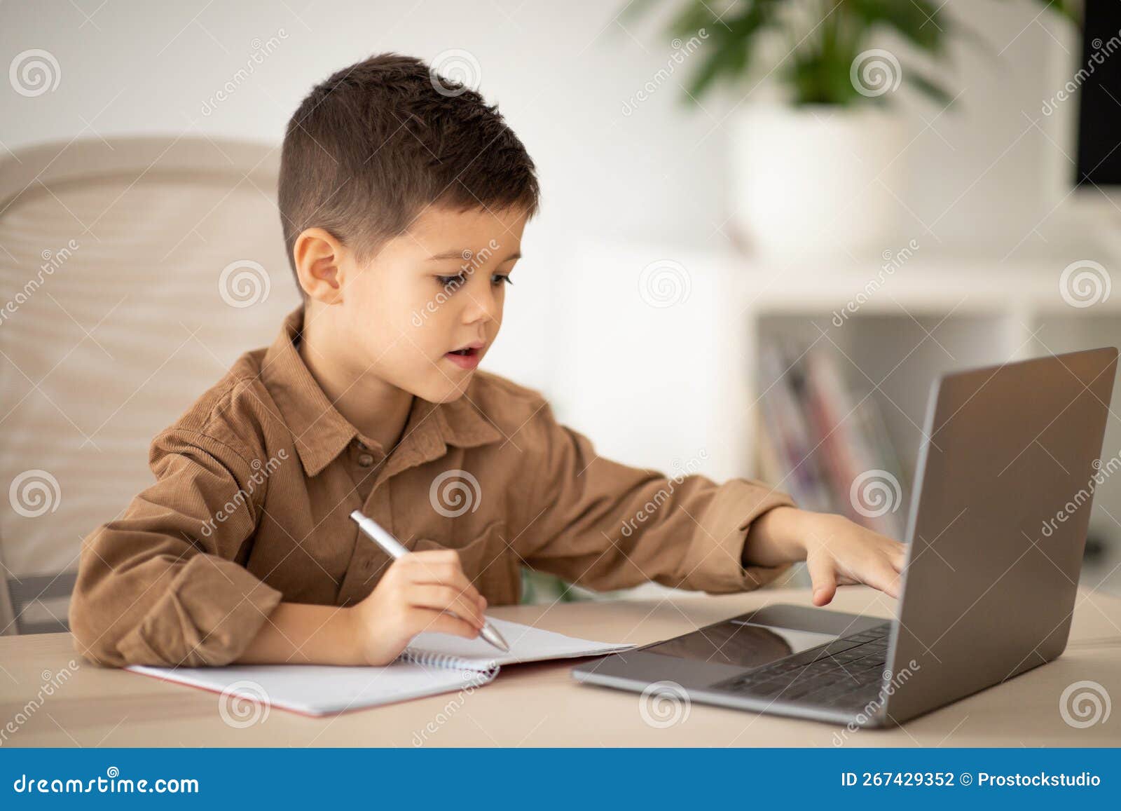 Serious Busy Little Boy Sits at Table, Studies, Has Video Call on ...