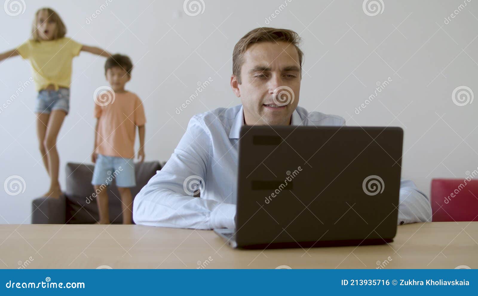 Serious Dad Working Via Laptop and Kids Jumping on Background Stock ...