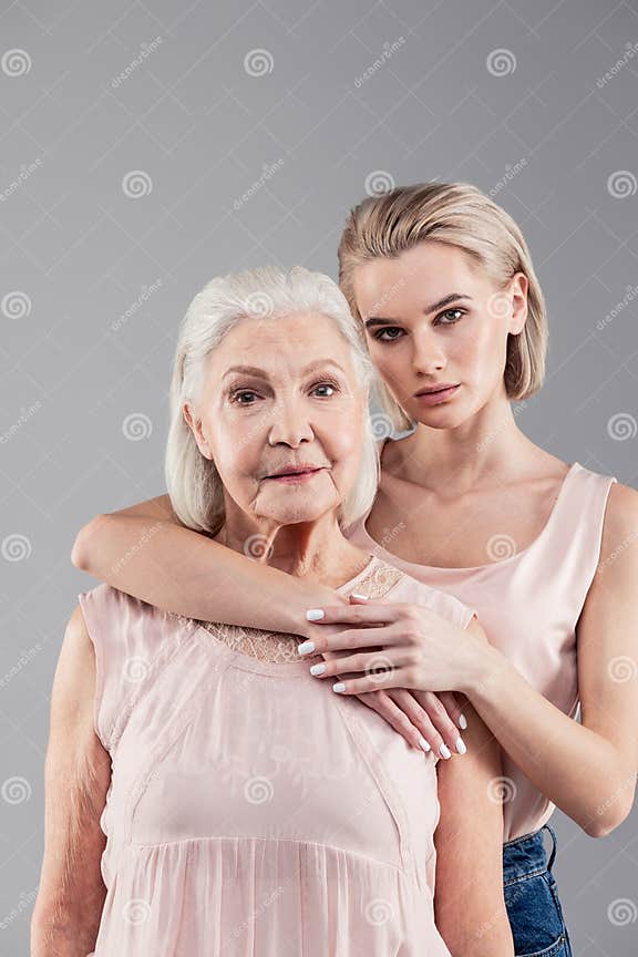 Beautiful Blonde Daughter With Neutral Face Expression Hugging Her